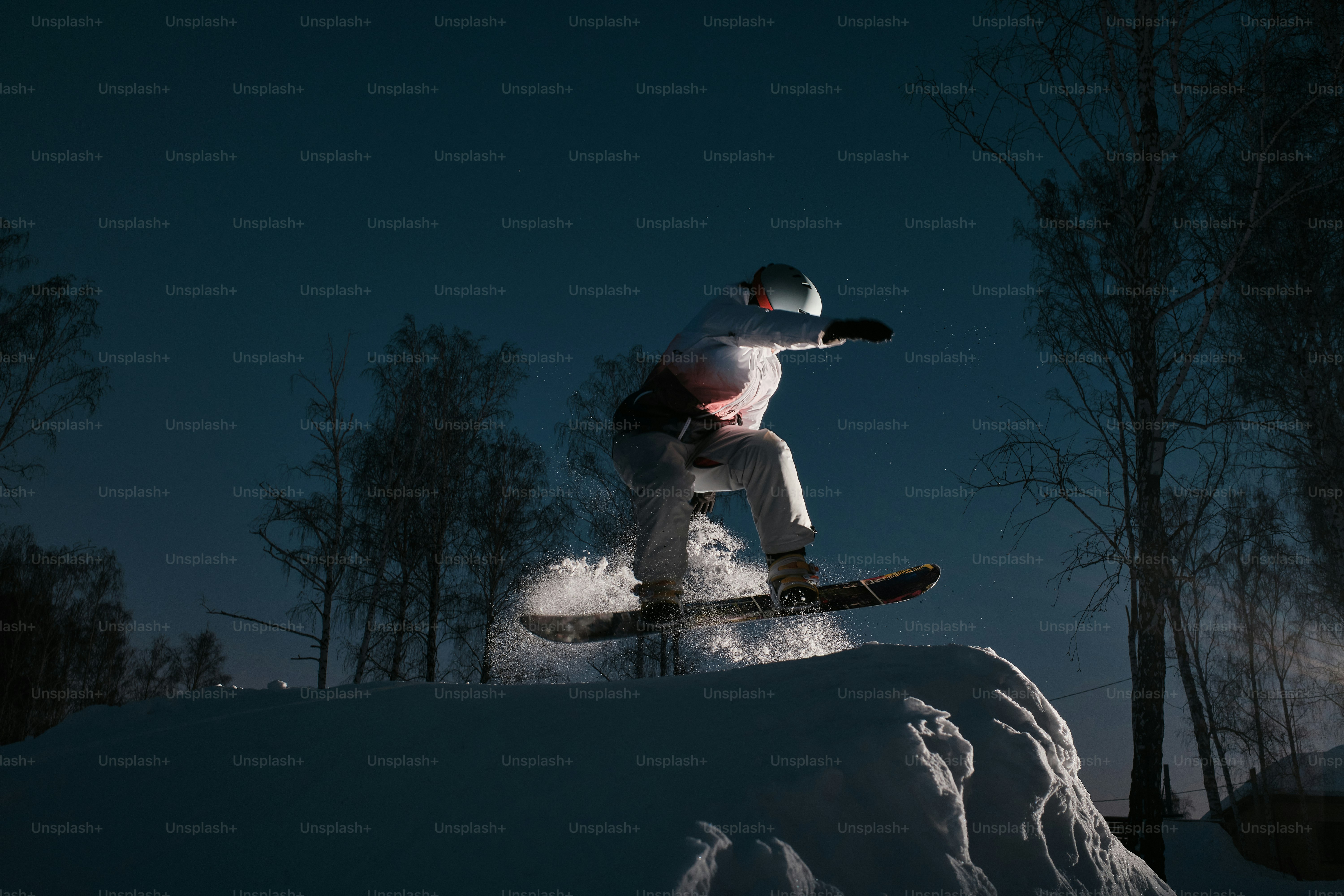 A man riding a snowboard down the side of a snow covered slope photo ...