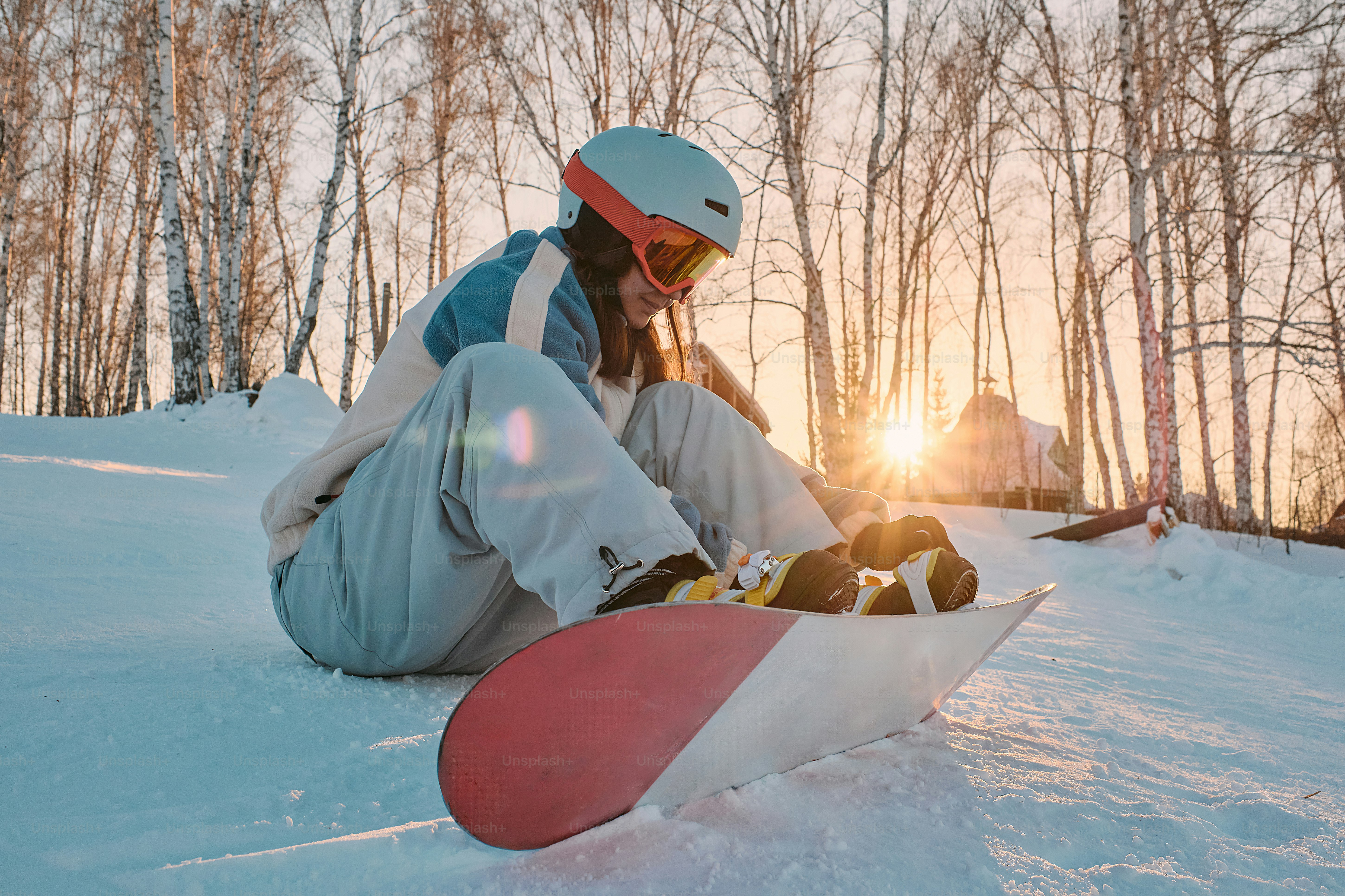 A snowboarder is sitting in the snow with his board photo ...