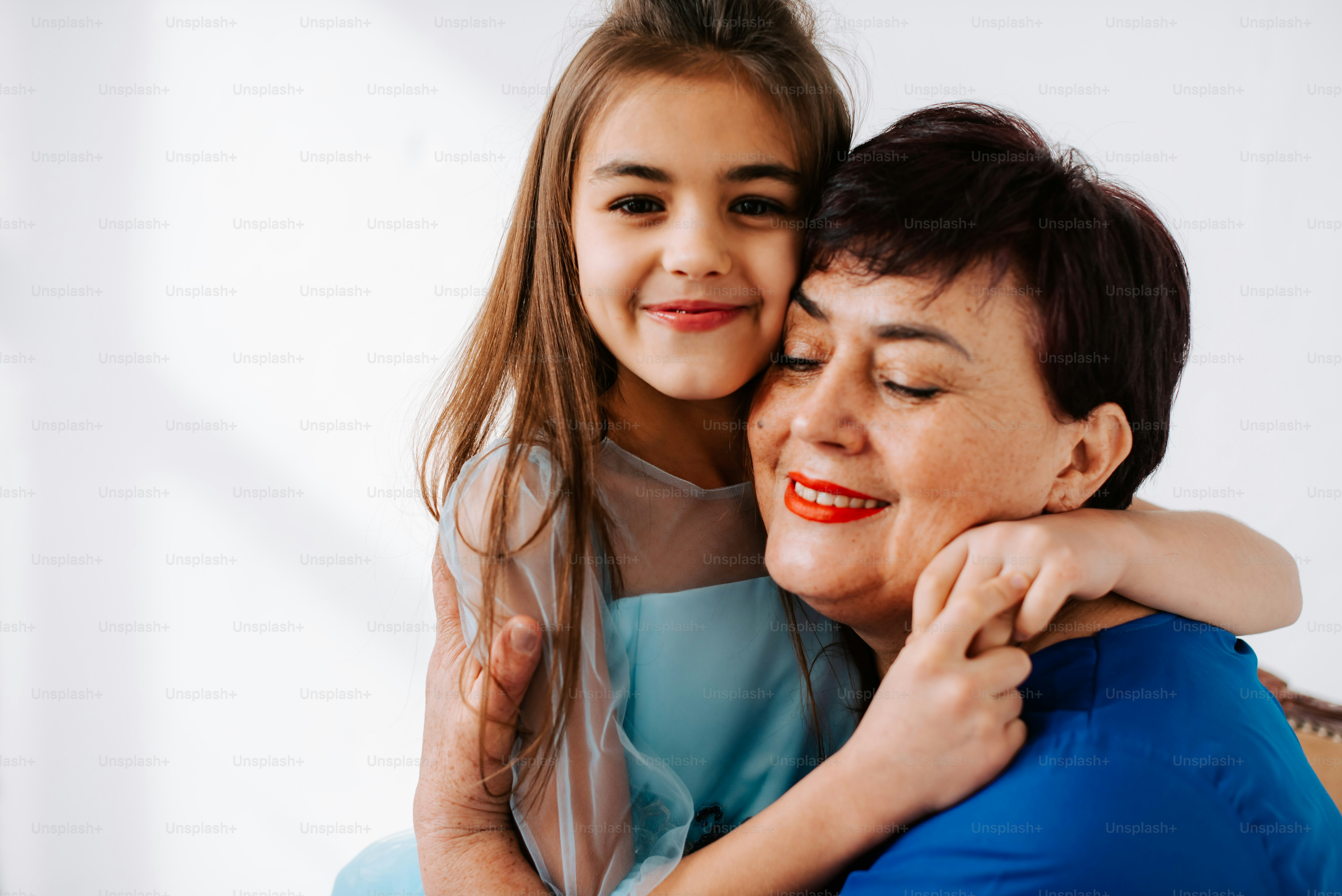 A woman hugging a little girl who is wearing a blue dress photo ...