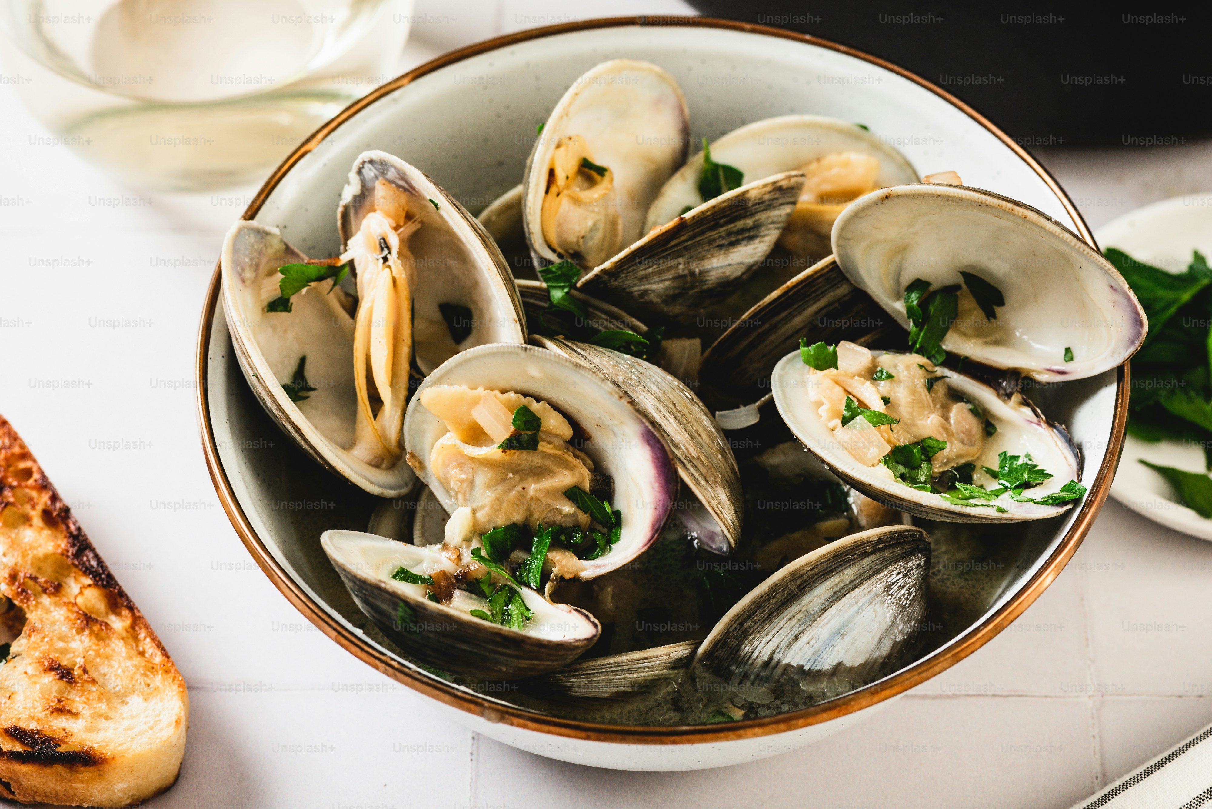 A bowl of clams with a slice of bread on the side photo – Seafood Image ...