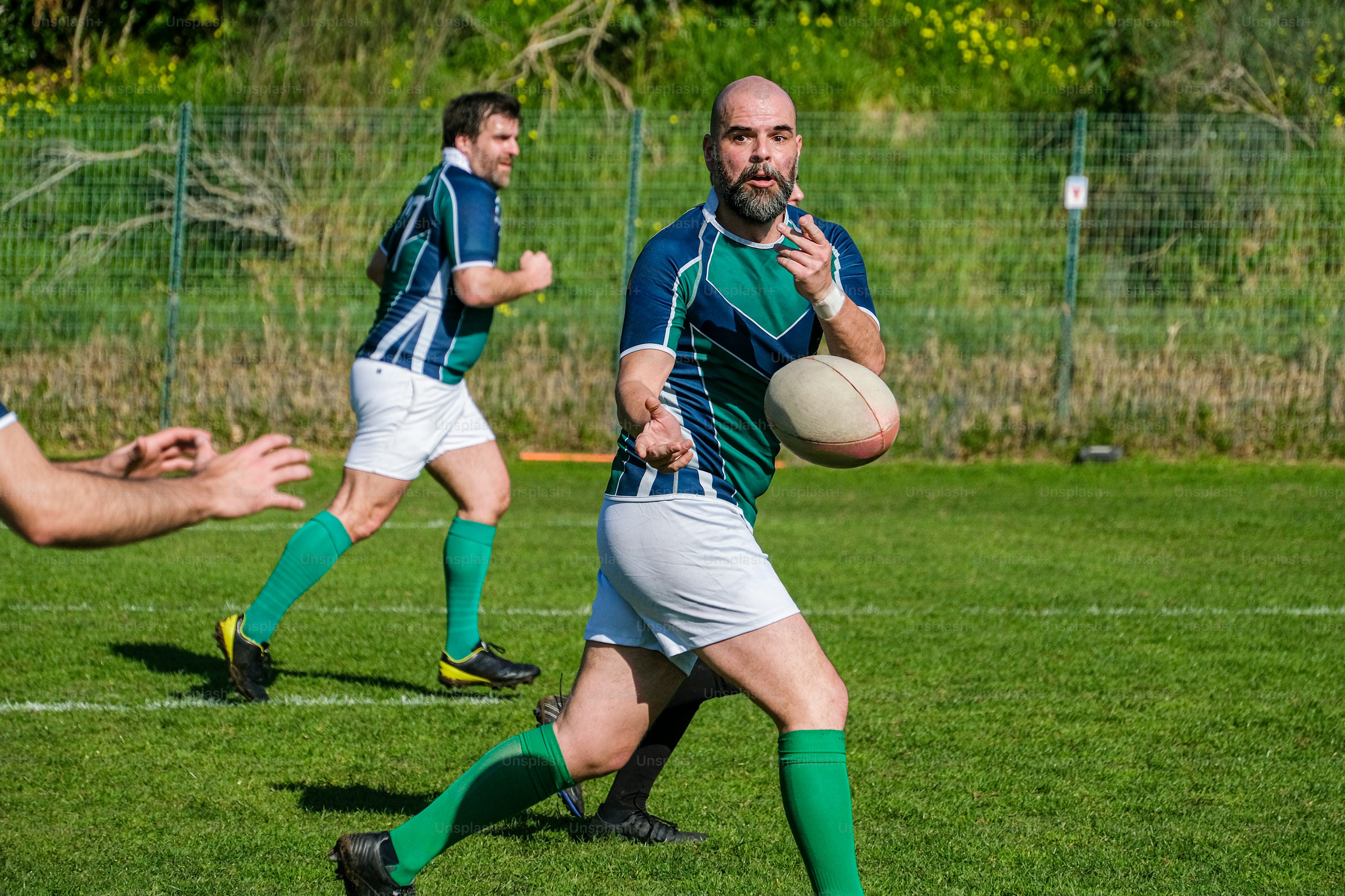 A group of men playing a game of frisbee on a field photo – Rugby ball ...