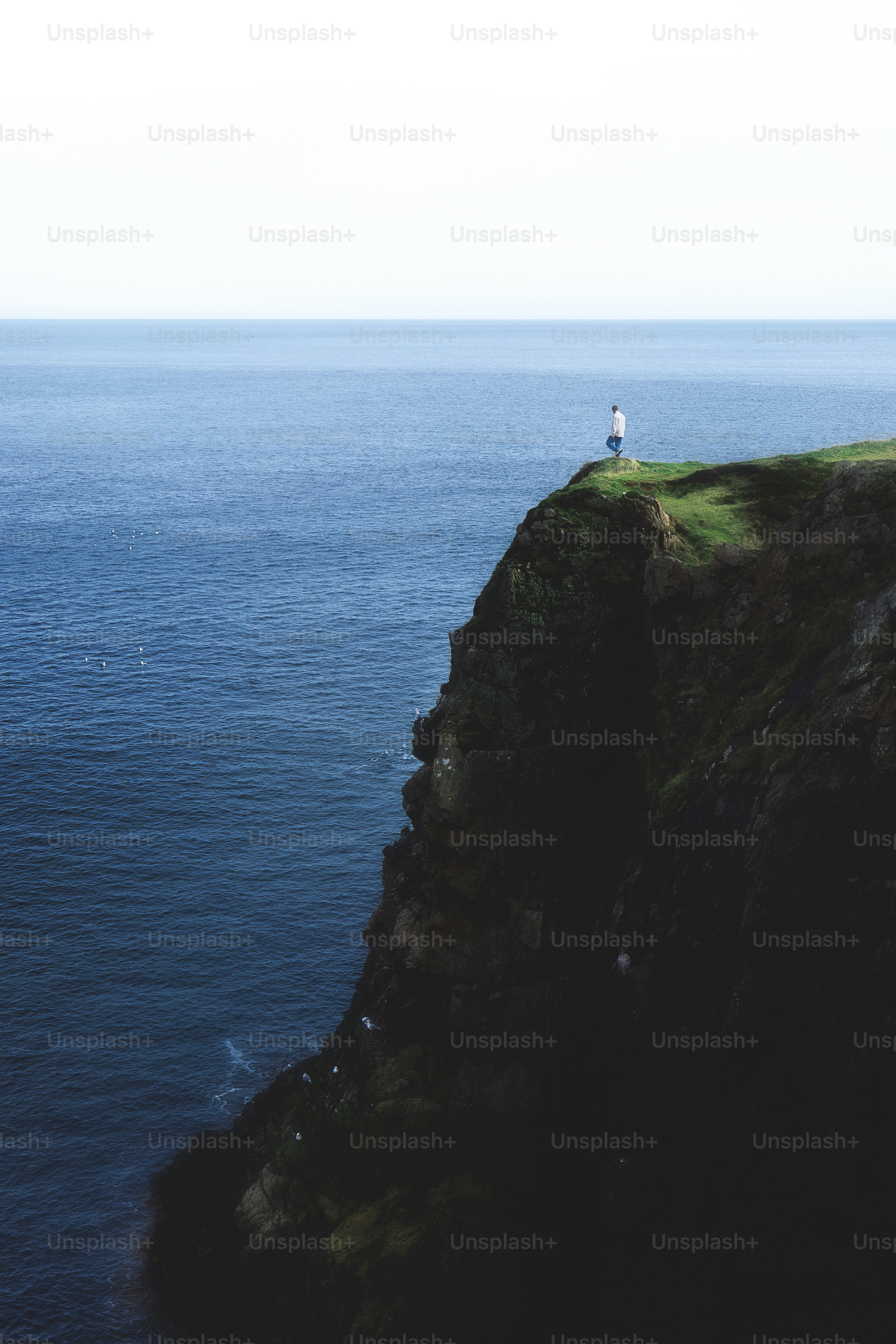 A person standing on a cliff overlooking the ocean photo – Scenery ...