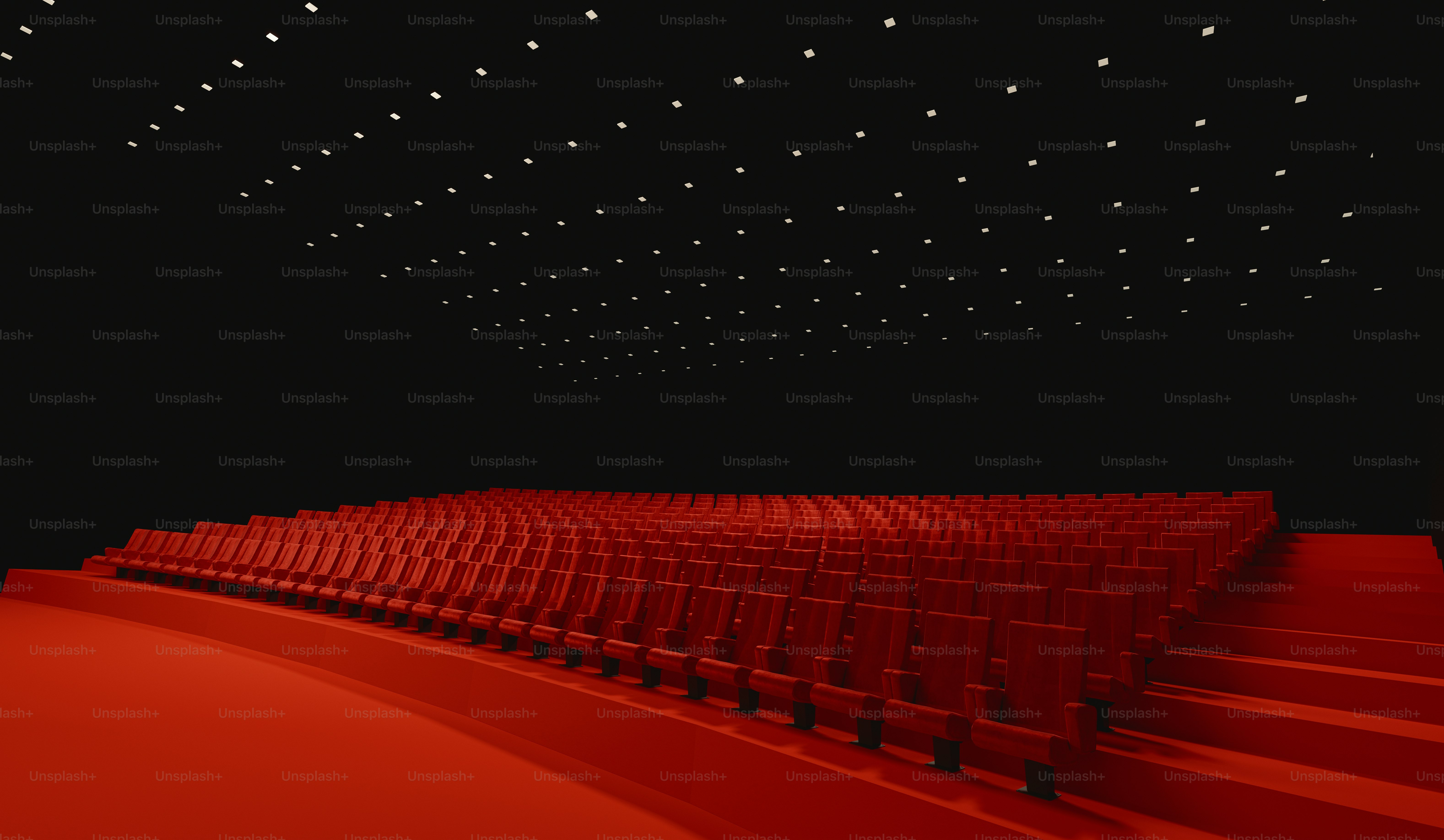A red carpeted room with rows of red chairs in front of a large screen ...