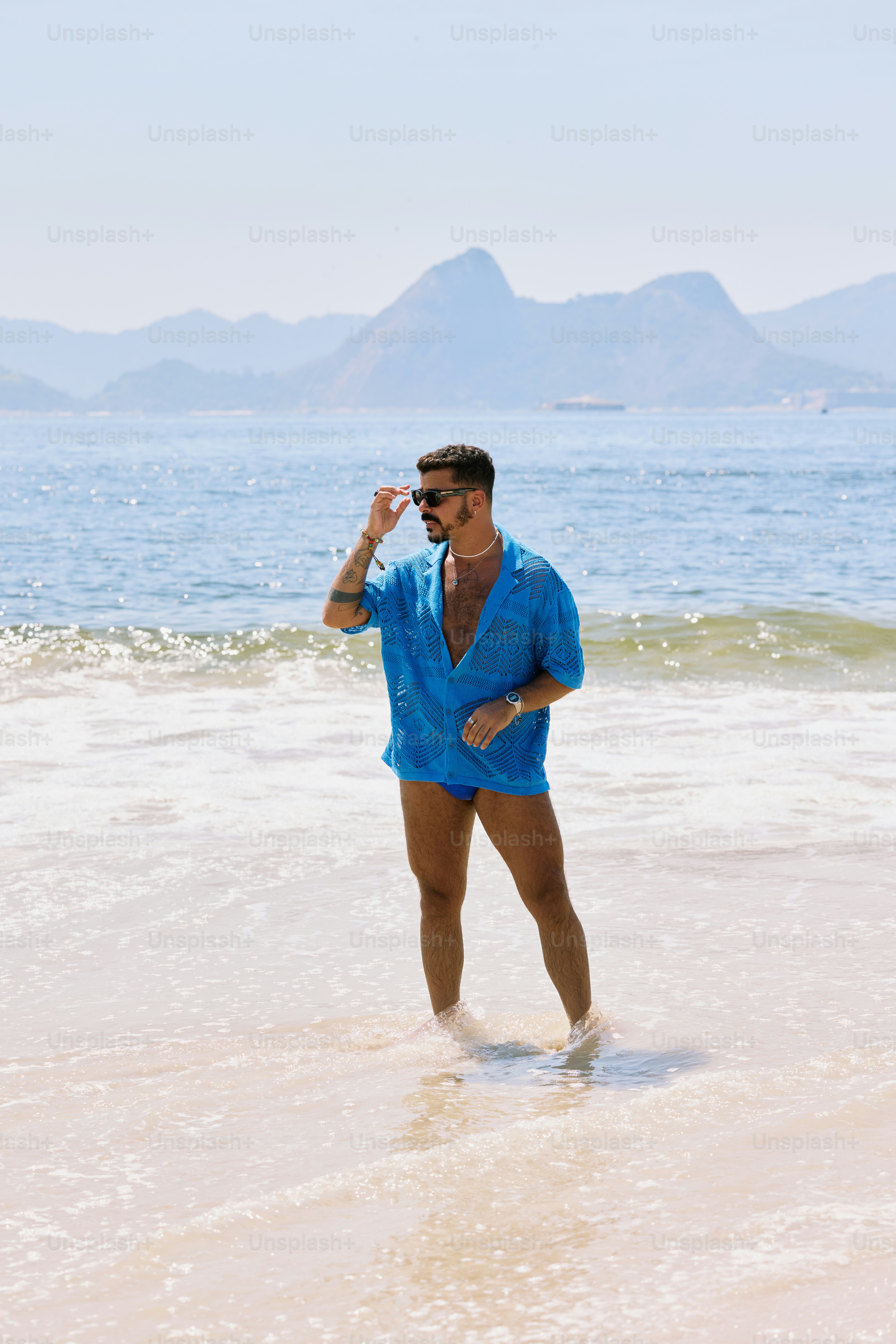 A man in a blue shirt is standing in the water photo – Gay Image on ...