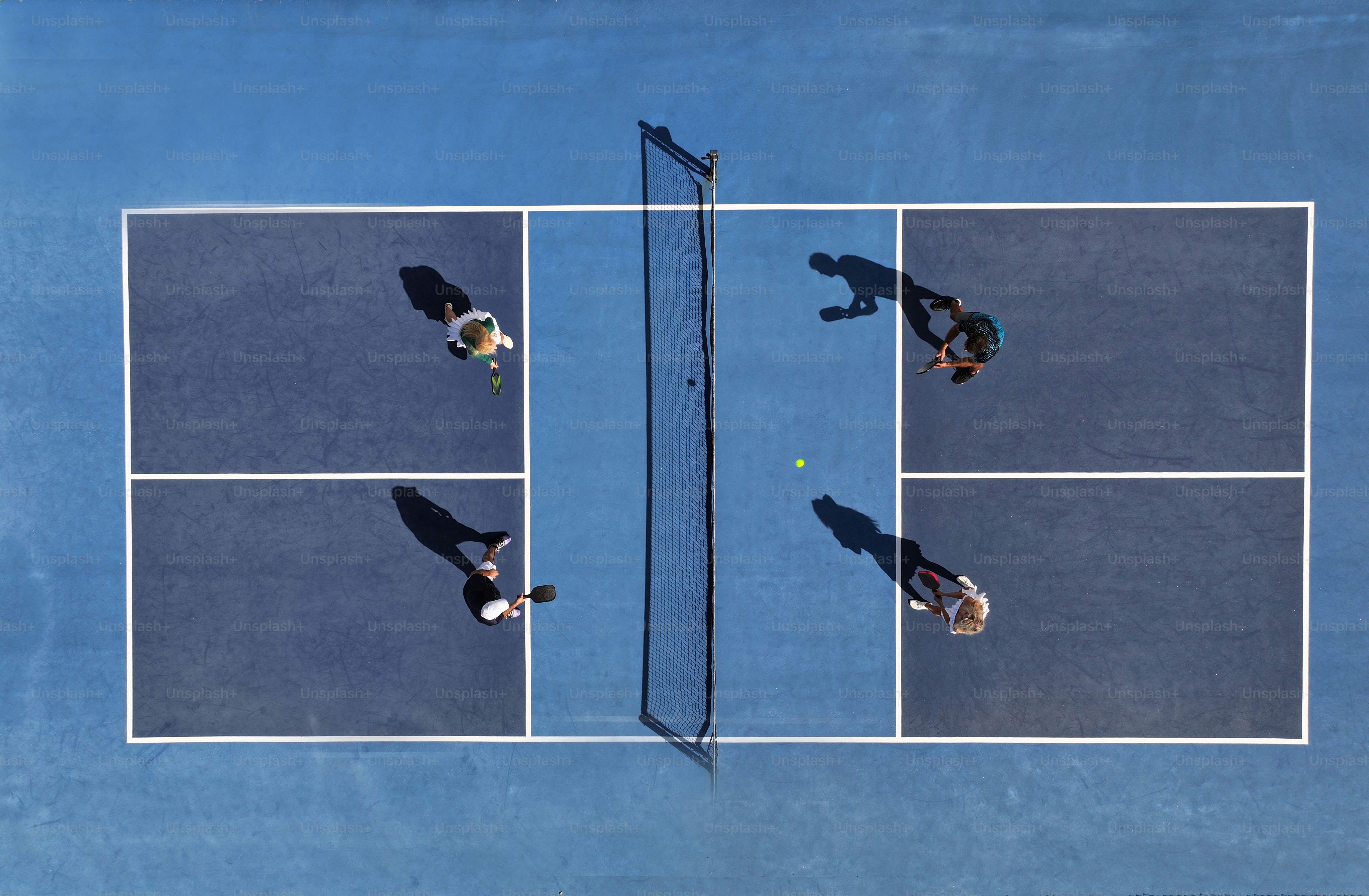Three people playing tennis on a blue tennis court photo – Pickle ball ...