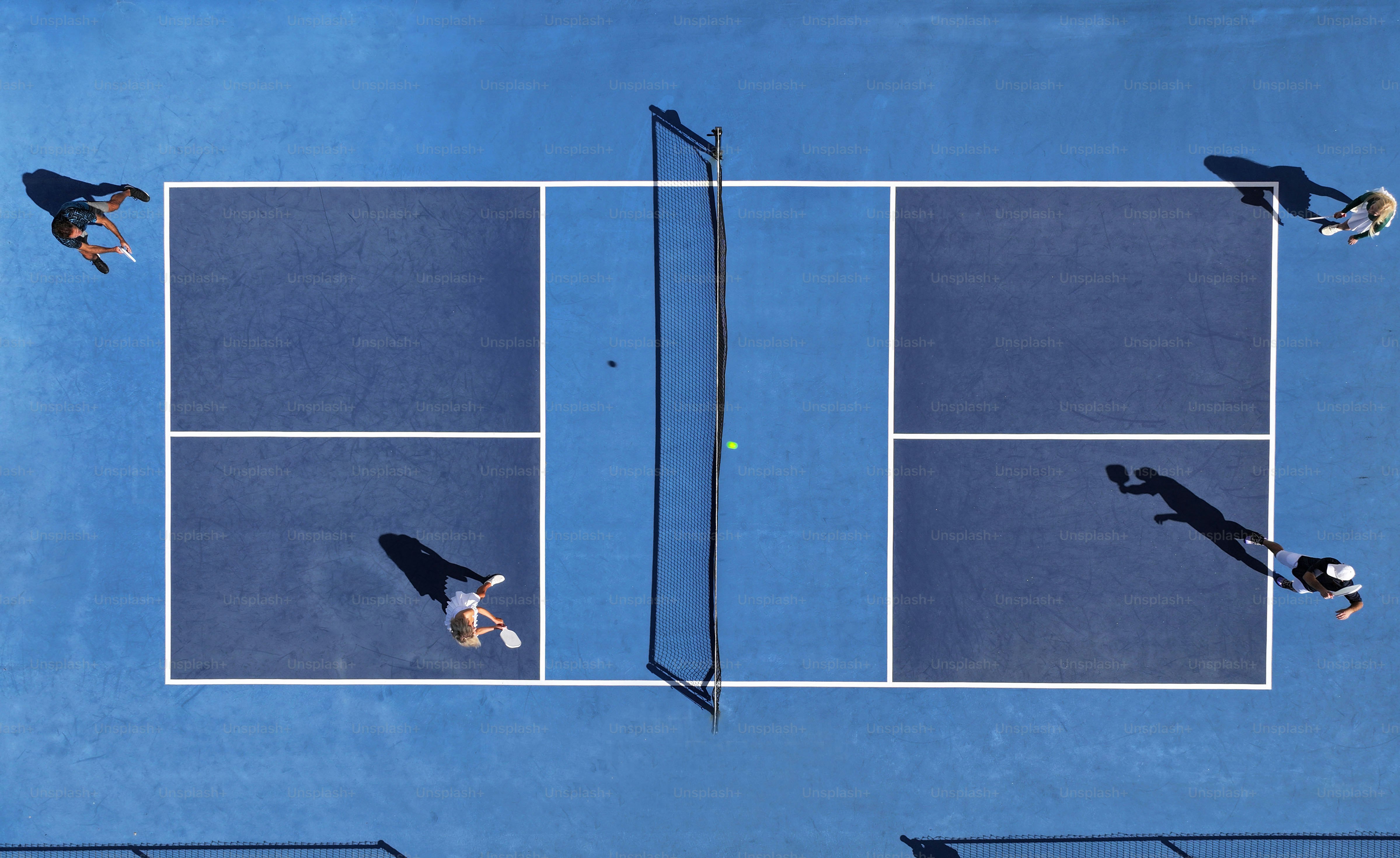 Two people playing tennis on a blue tennis court photo – Racket Image ...