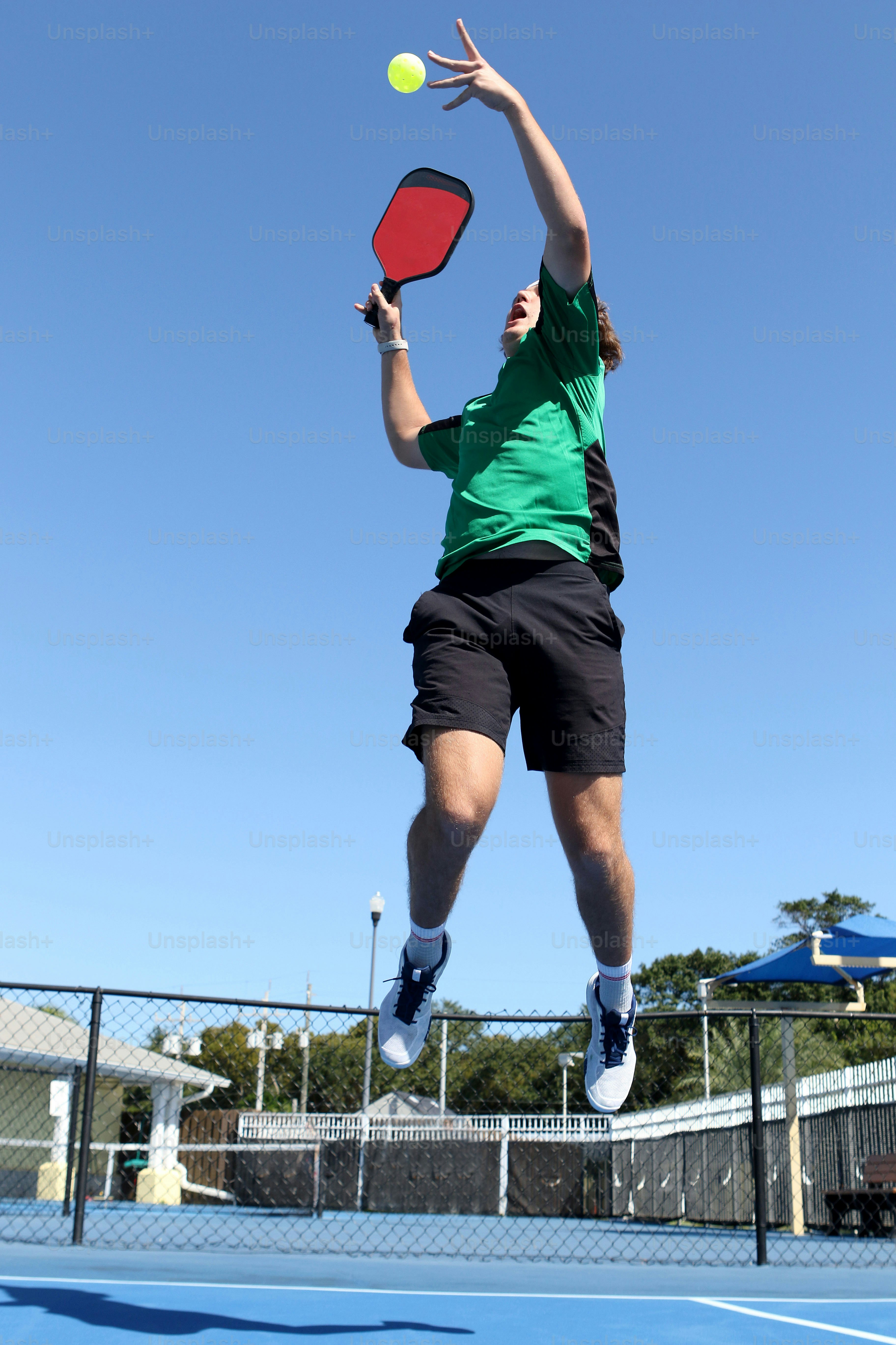 A man jumping in the air to hit a tennis ball photo – Sports Image on ...