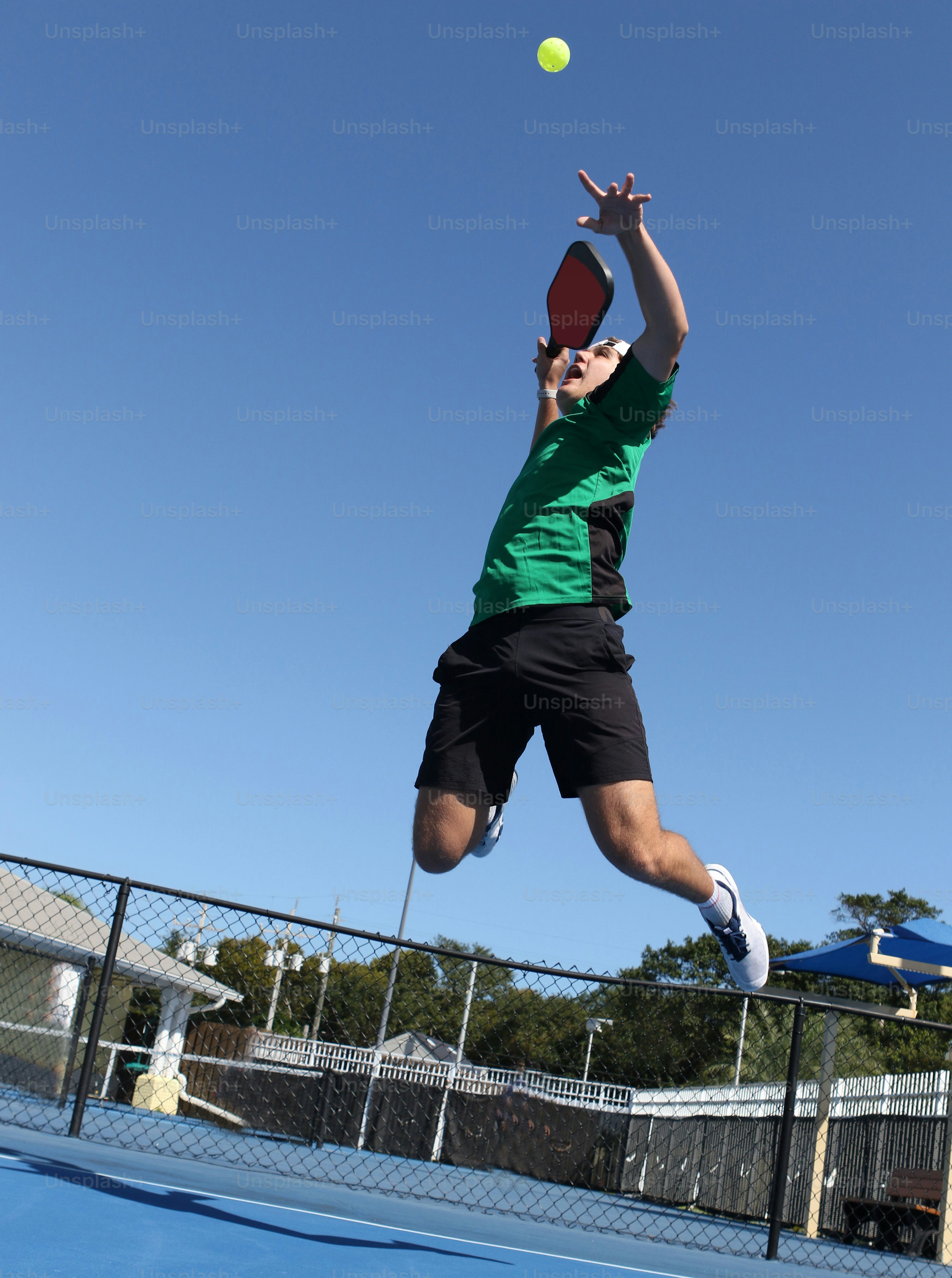 A man jumping in the air to hit a tennis ball photo – Sports Image on ...