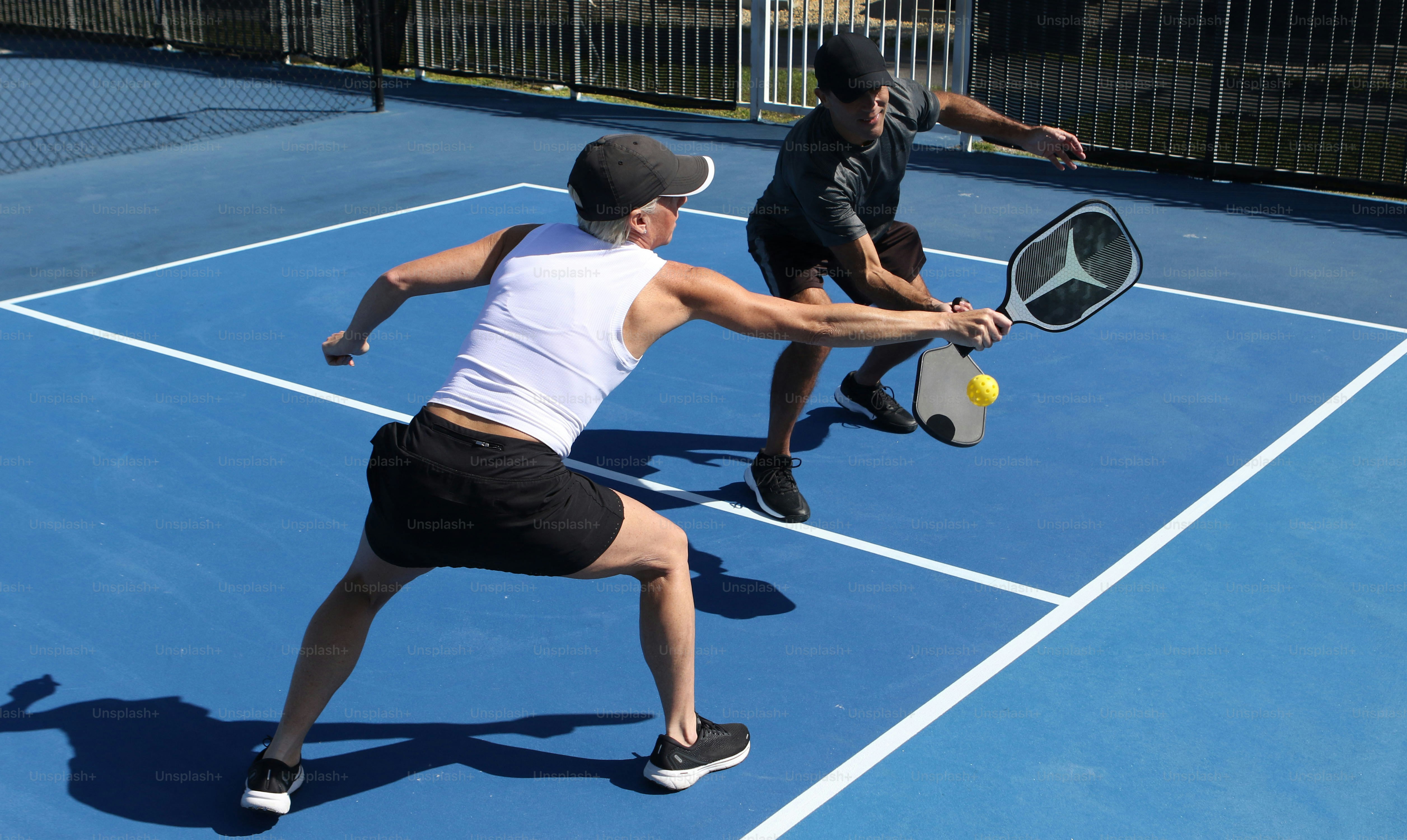 Foto Dos personas jugando al tenis en una cancha de tenis azul ...