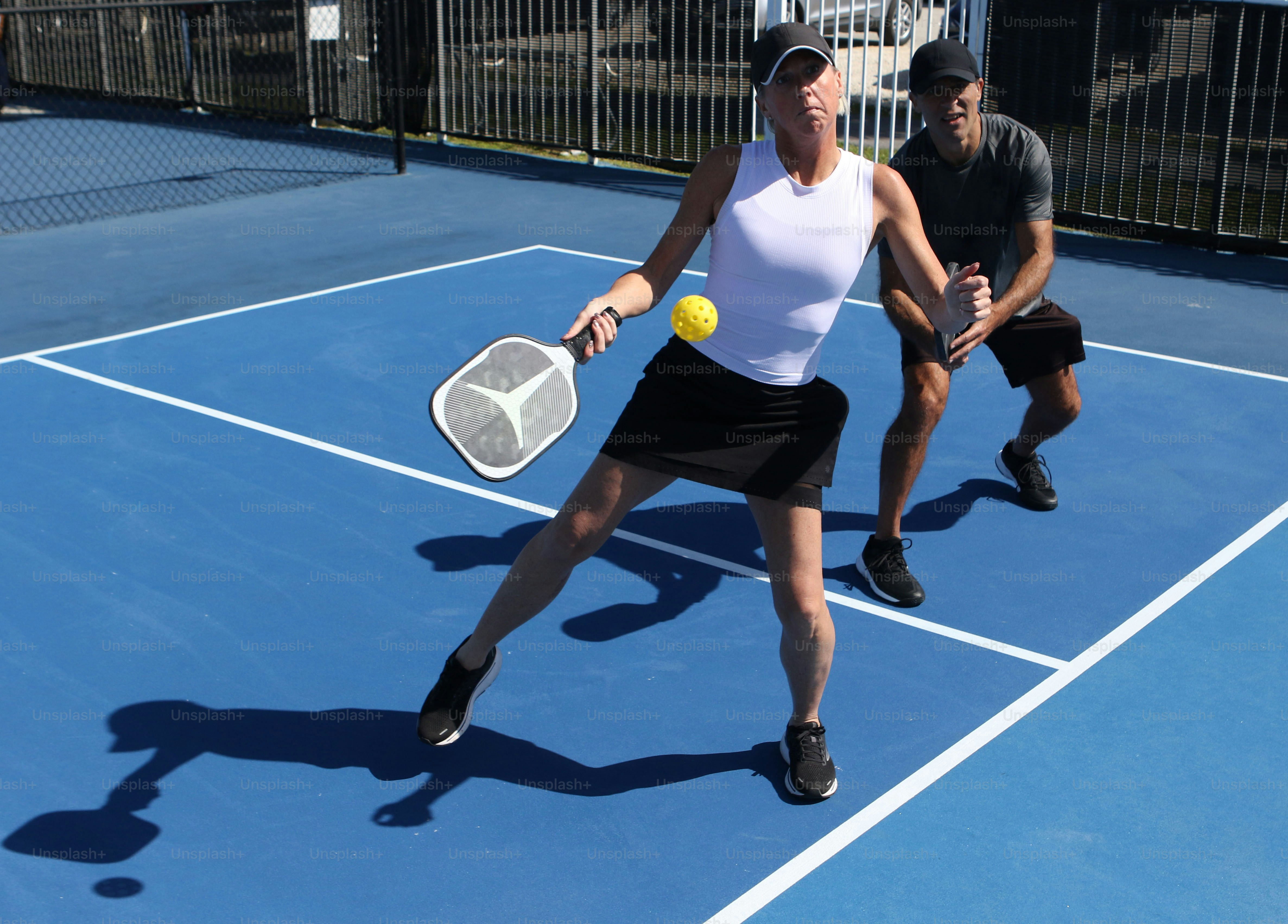 A woman holding a tennis racquet on a tennis court photo – Pickle ball ...