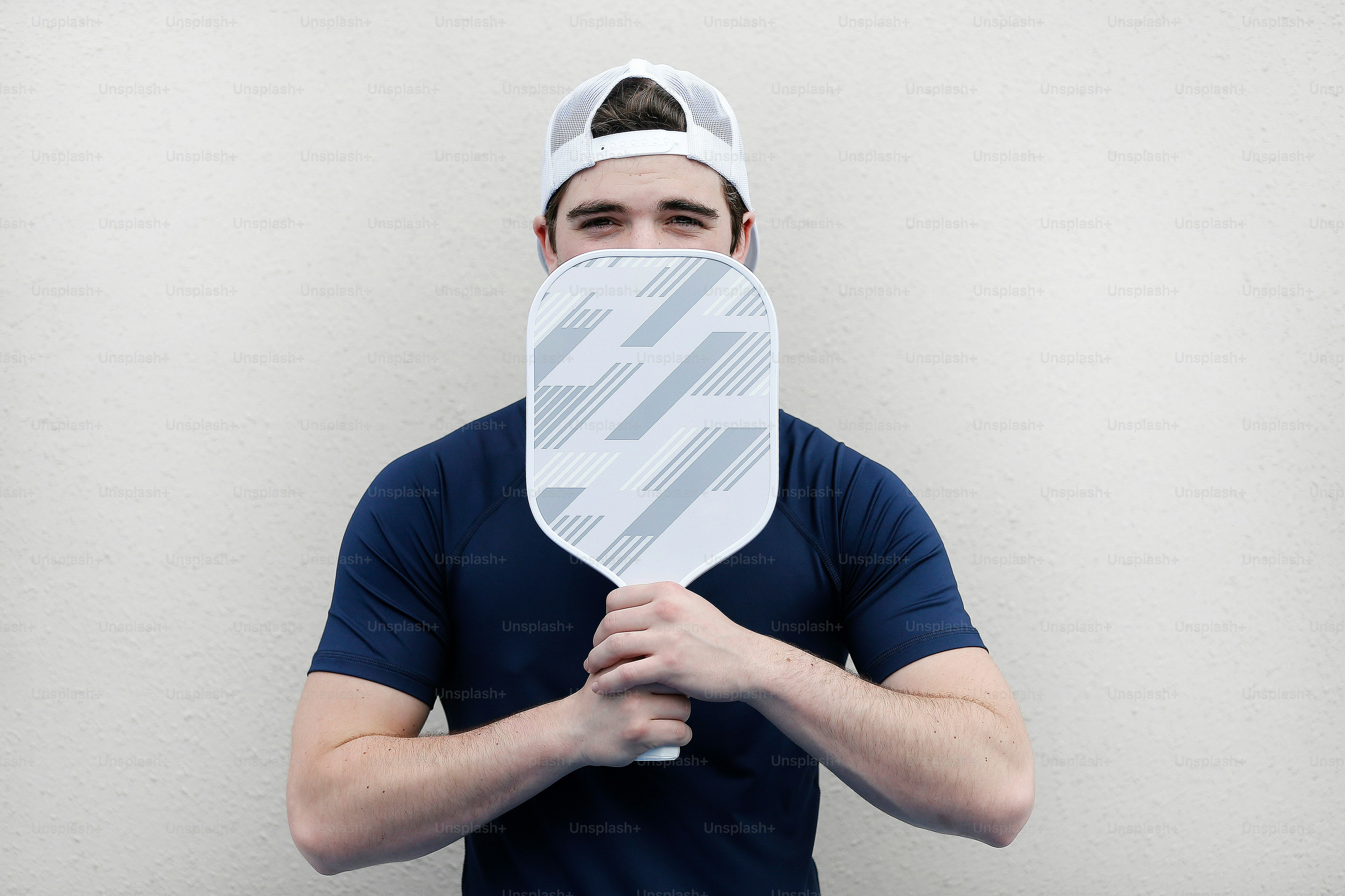 A man holding a paddle over his face photo – Pickleball racket Image on ...