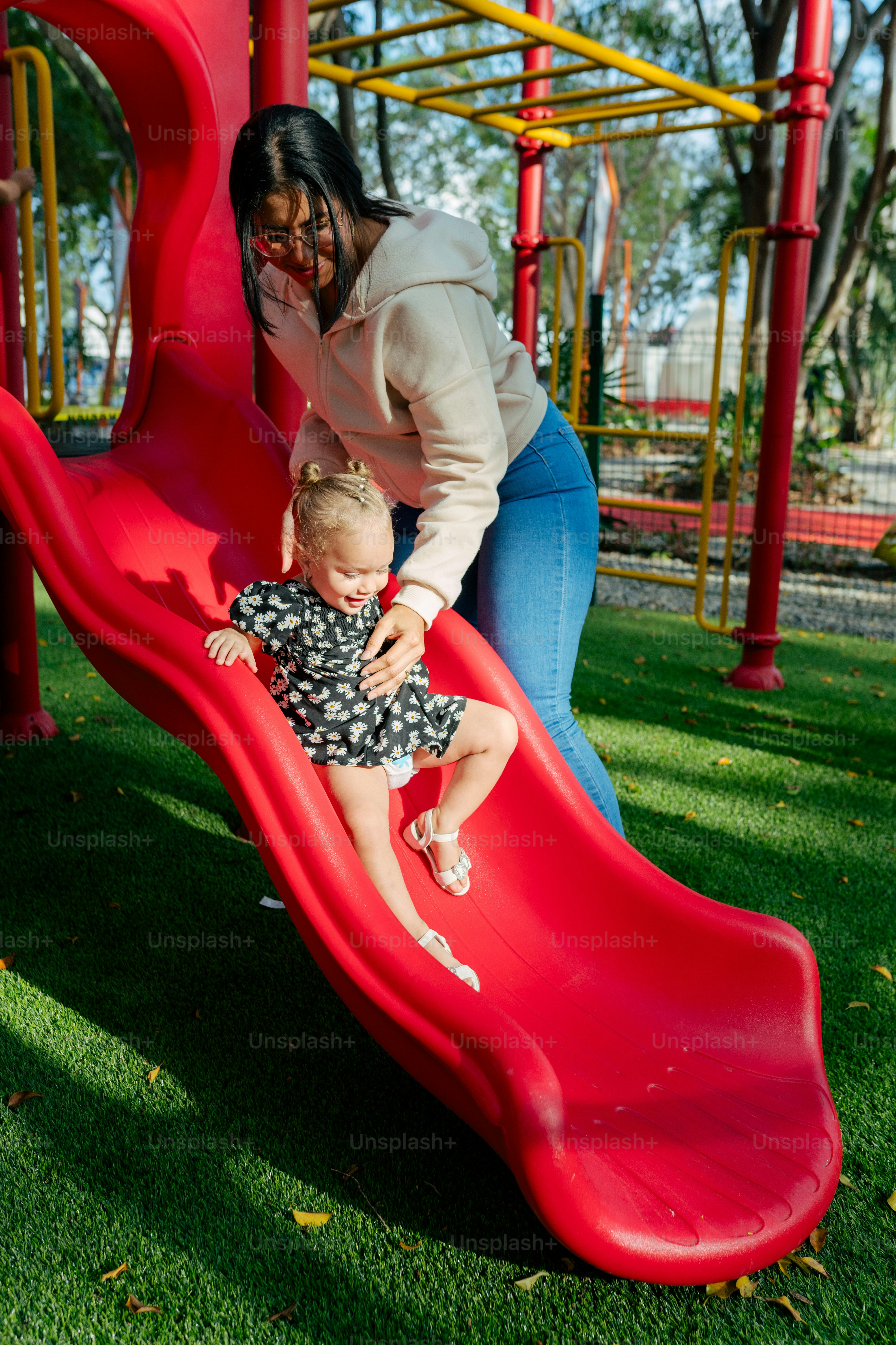 A woman and a child playing on a slide photo – Child Image on Unsplash
