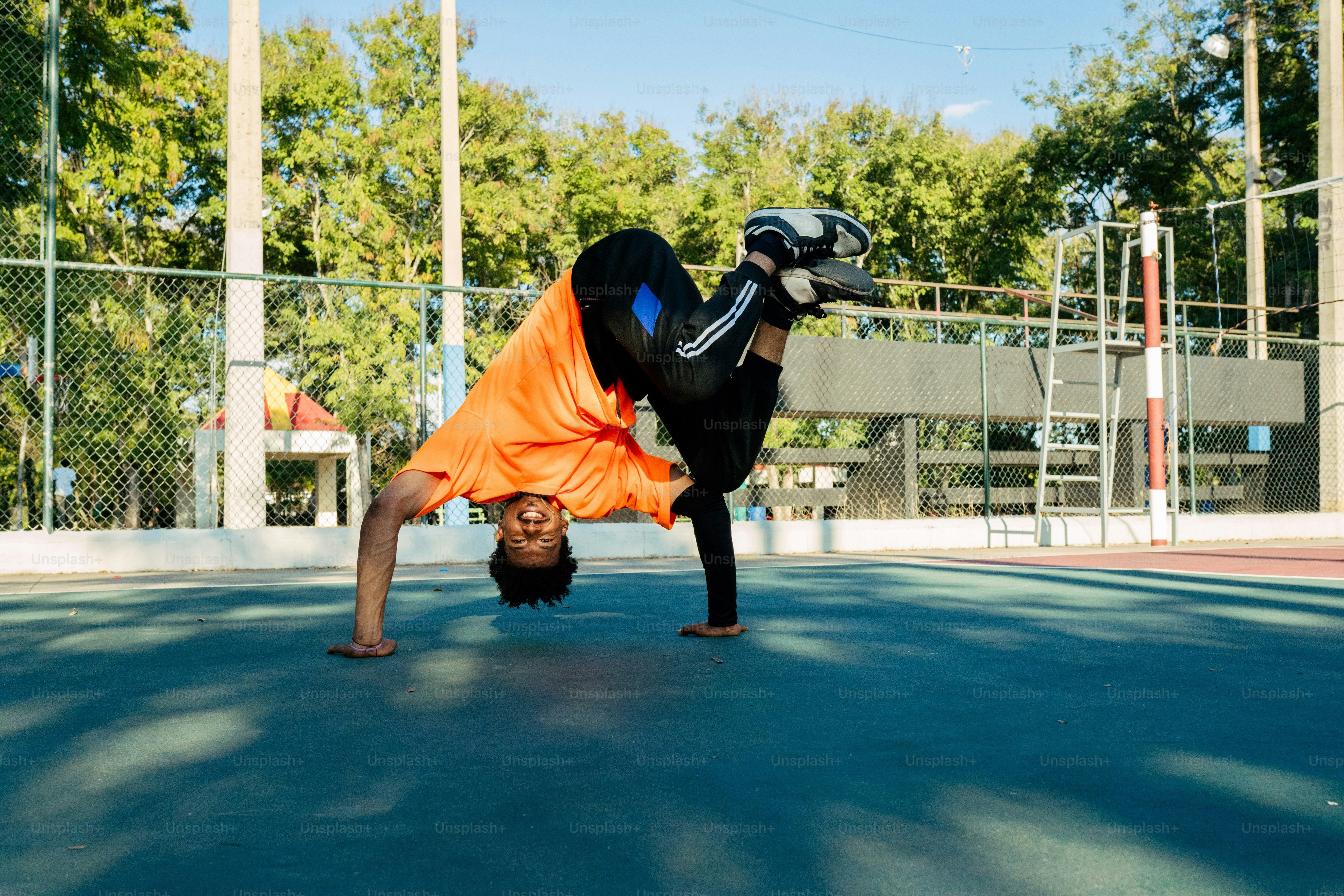 A person doing a handstand on a tennis court photo – Break dance Image ...