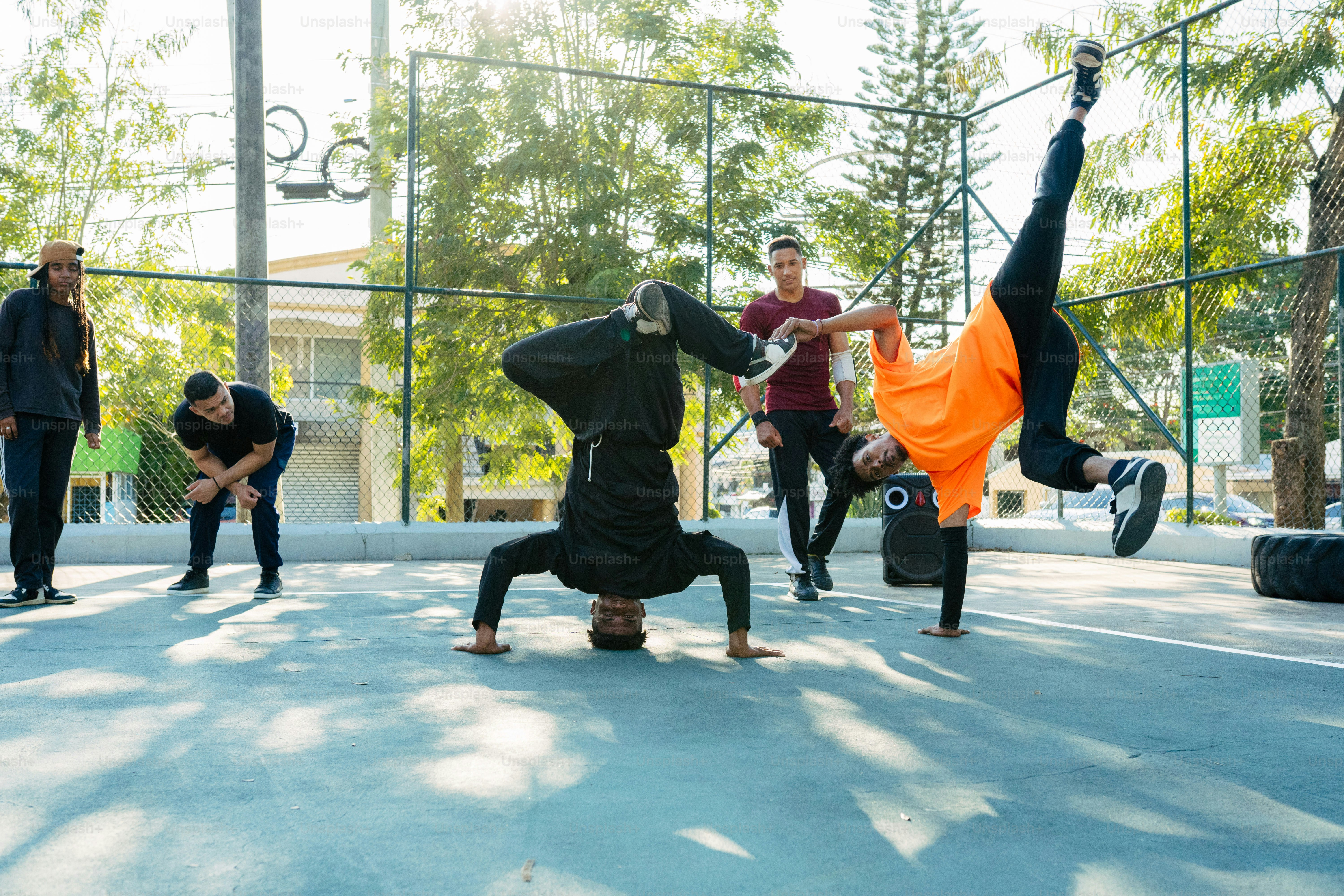 A group of people doing a handstand on a tennis court photo – Break ...