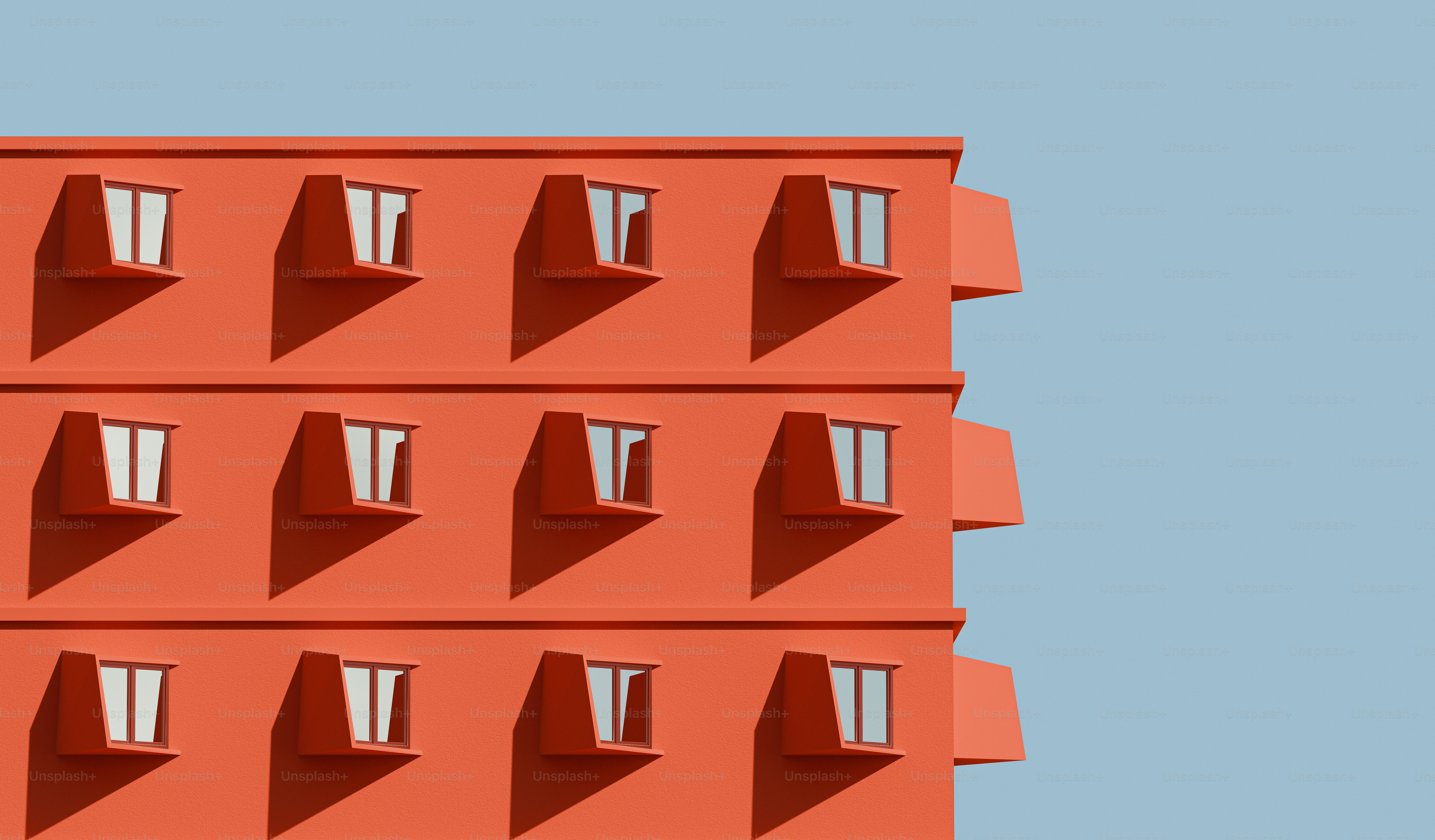 A tall red building with windows and a sky background photo – Building ...