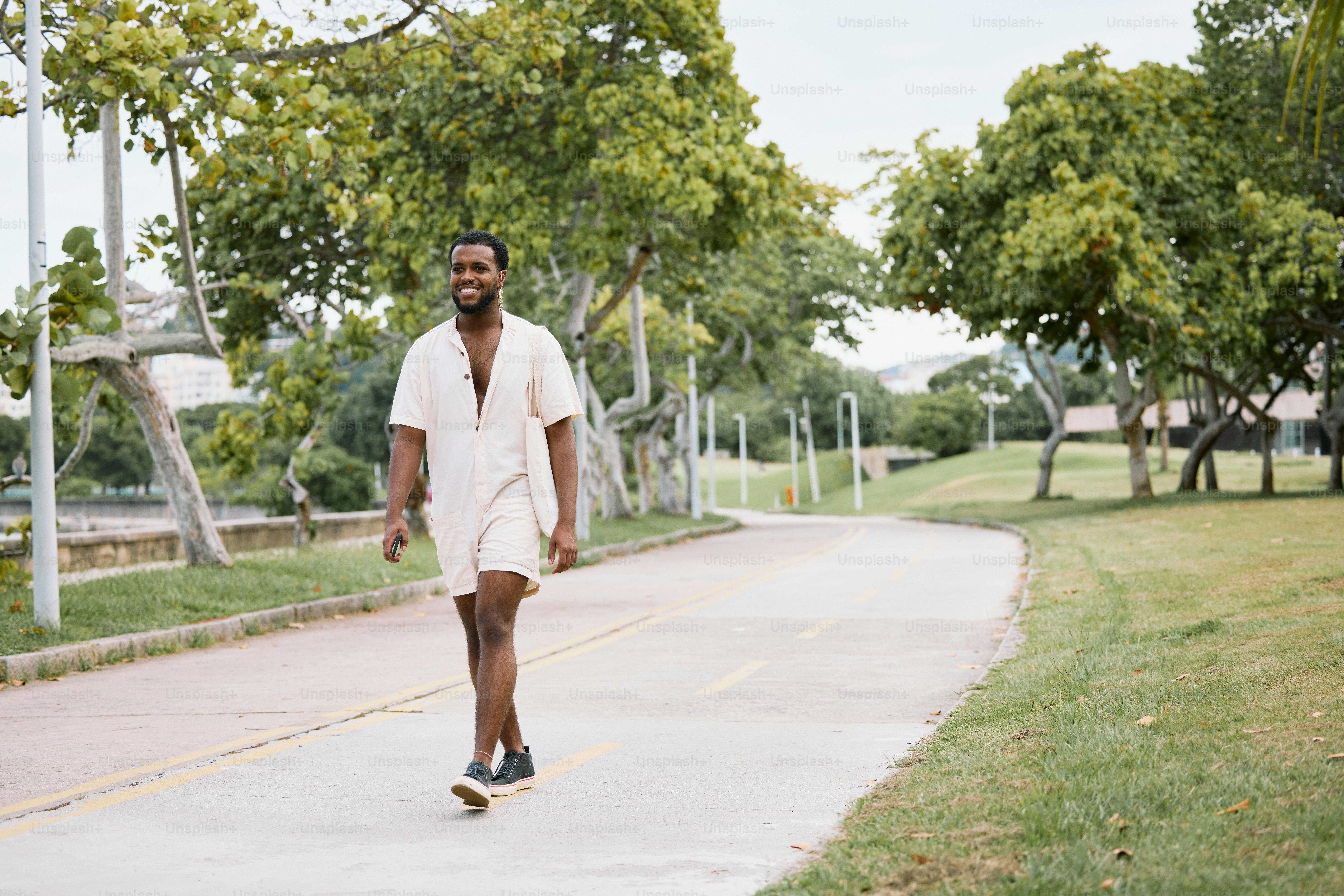 A man walking down a street with trees in the background photo – Gay ...