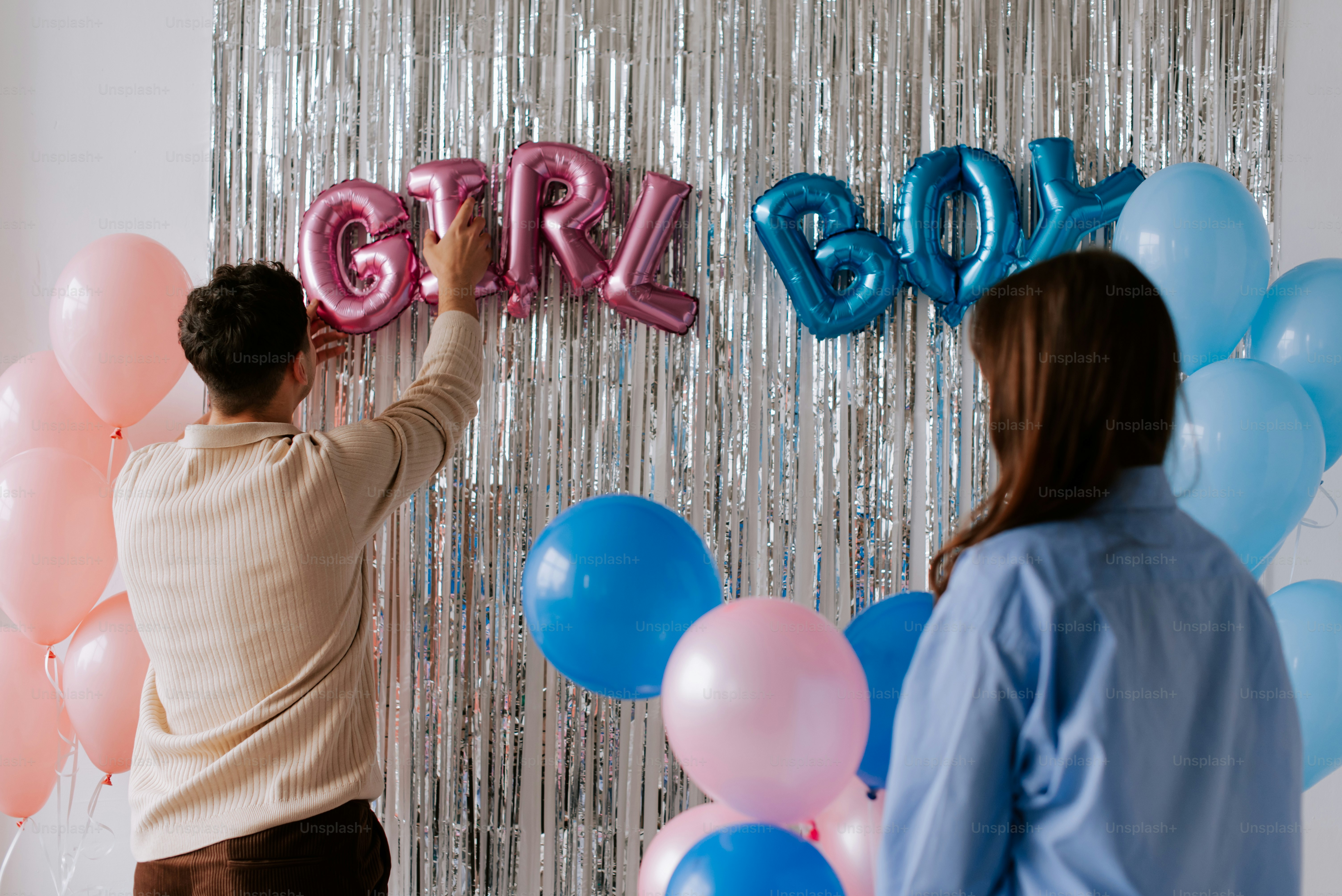 A man and a woman standing in front of a wall with balloons photo ...