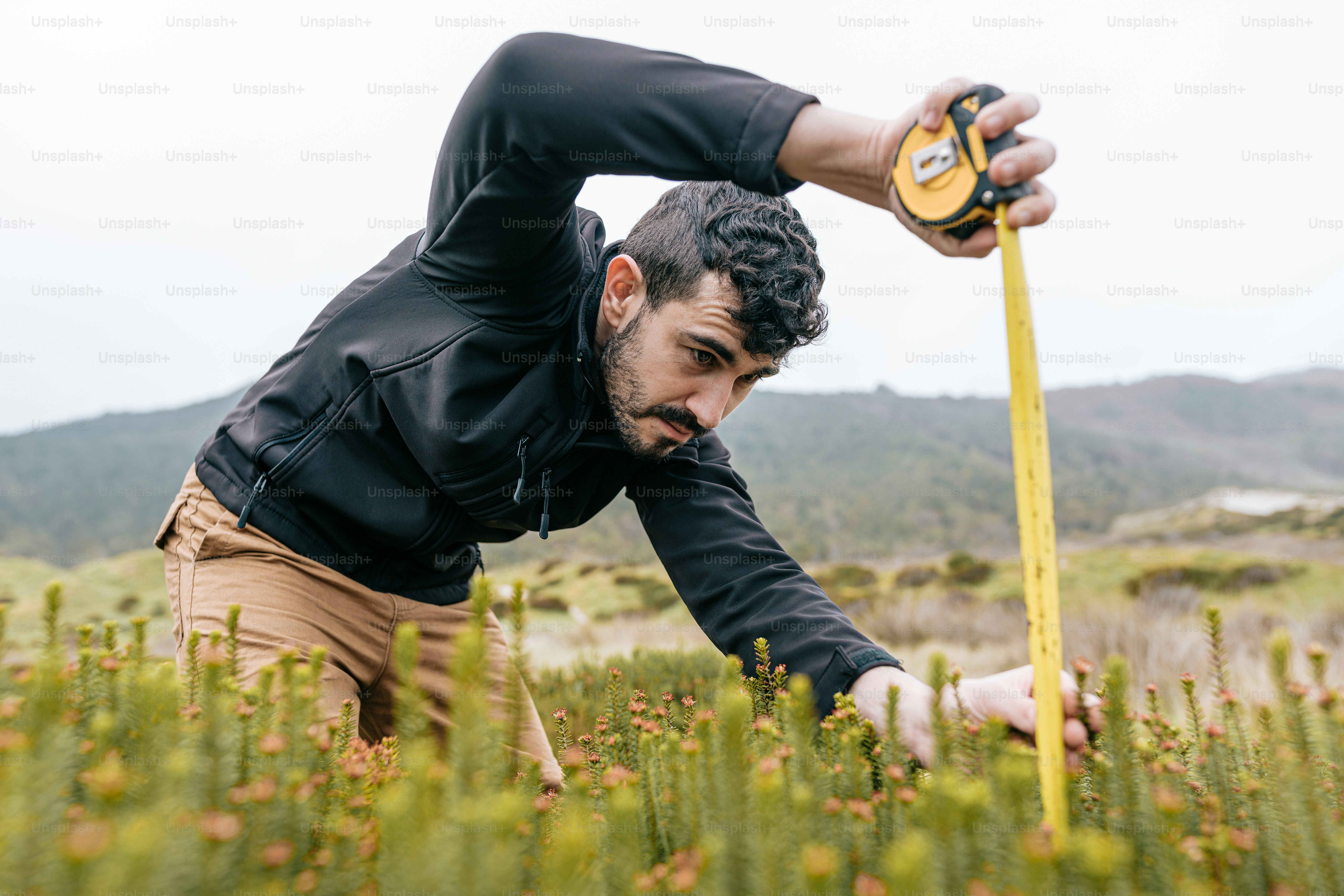 A man in a field with a measuring tape photo – Collecting data Image on ...