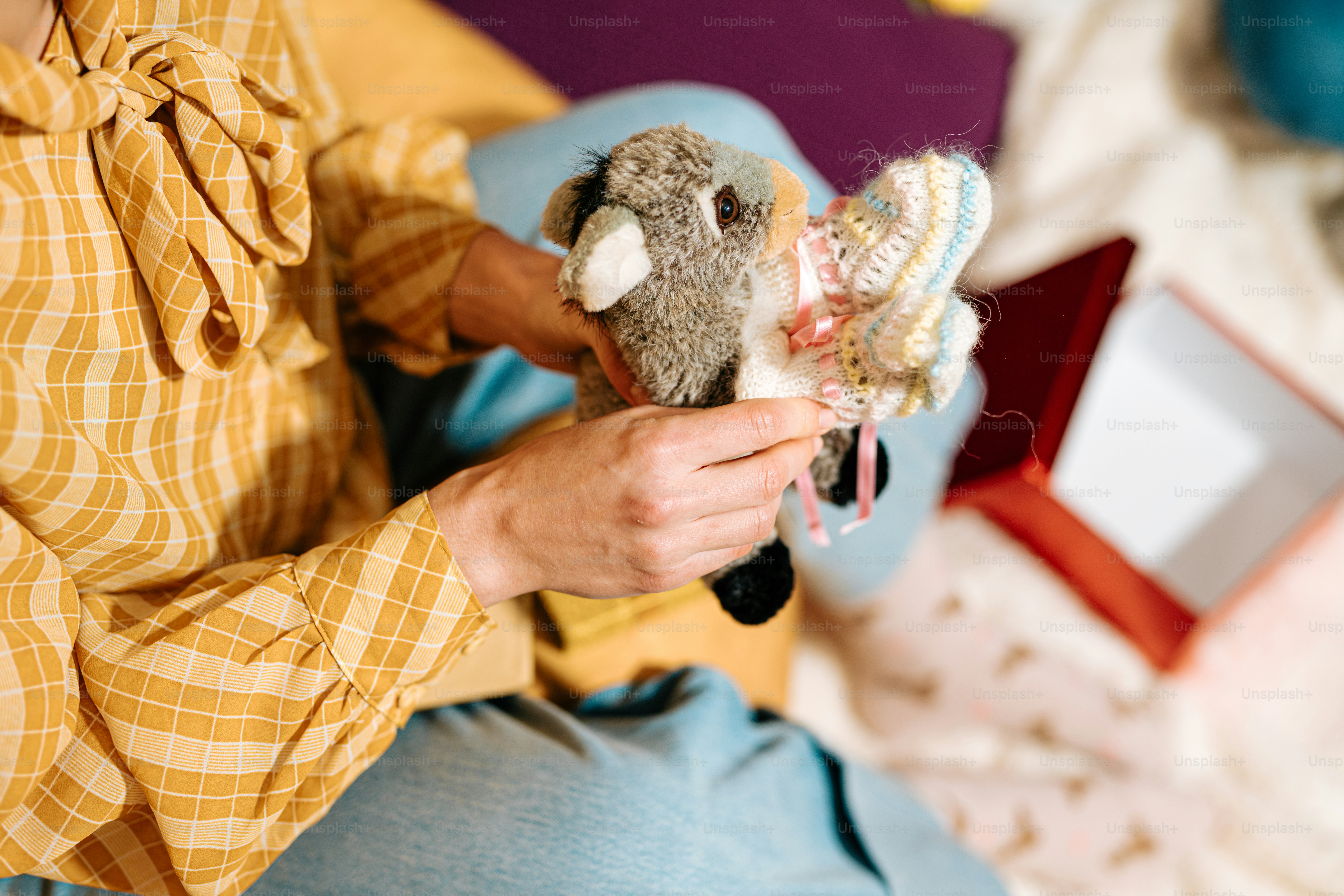 A person sitting on a couch holding a stuffed animal photo – Party ...