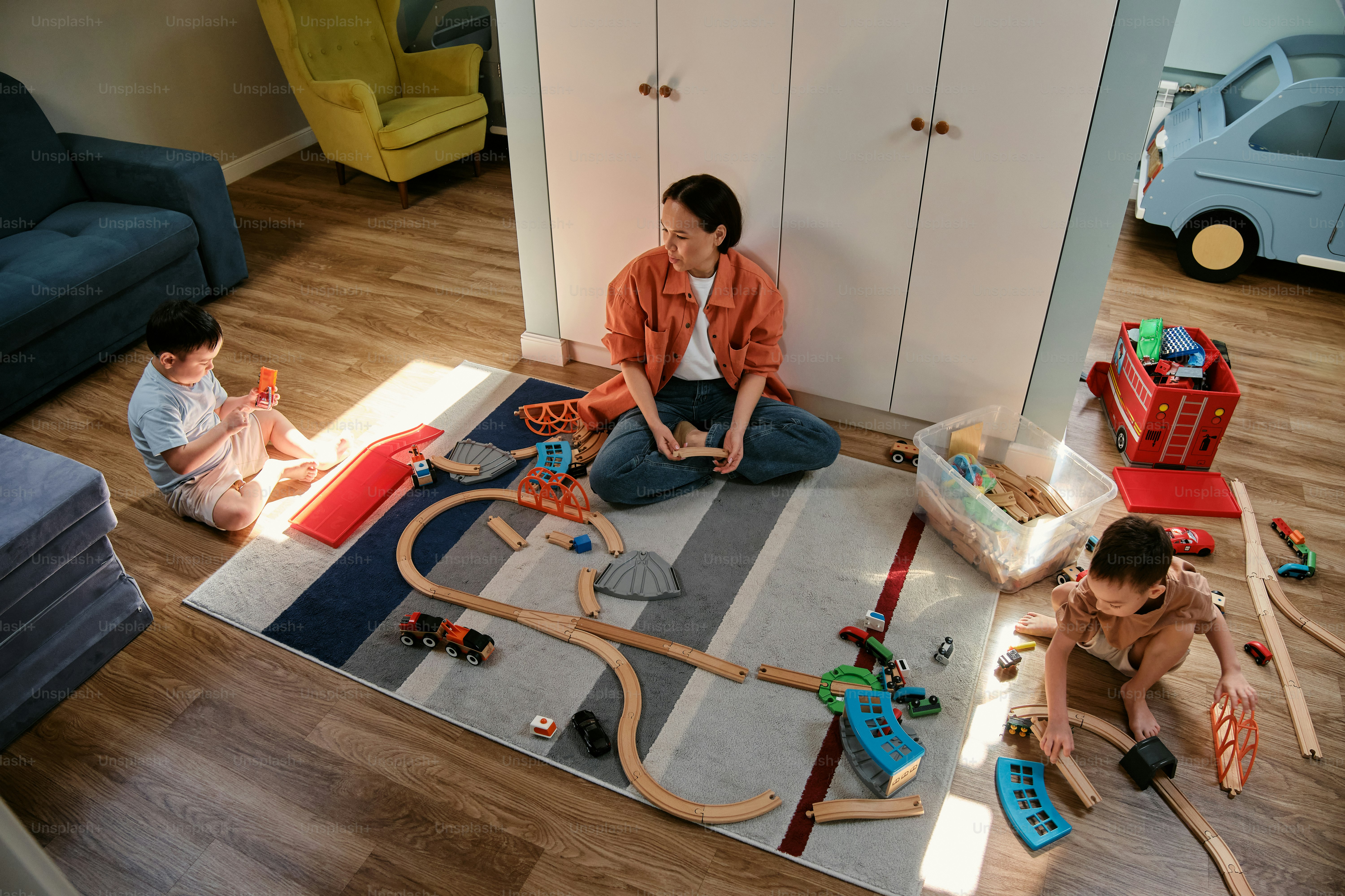 A woman and two boys playing with toys on the floor photo – Kids Image ...