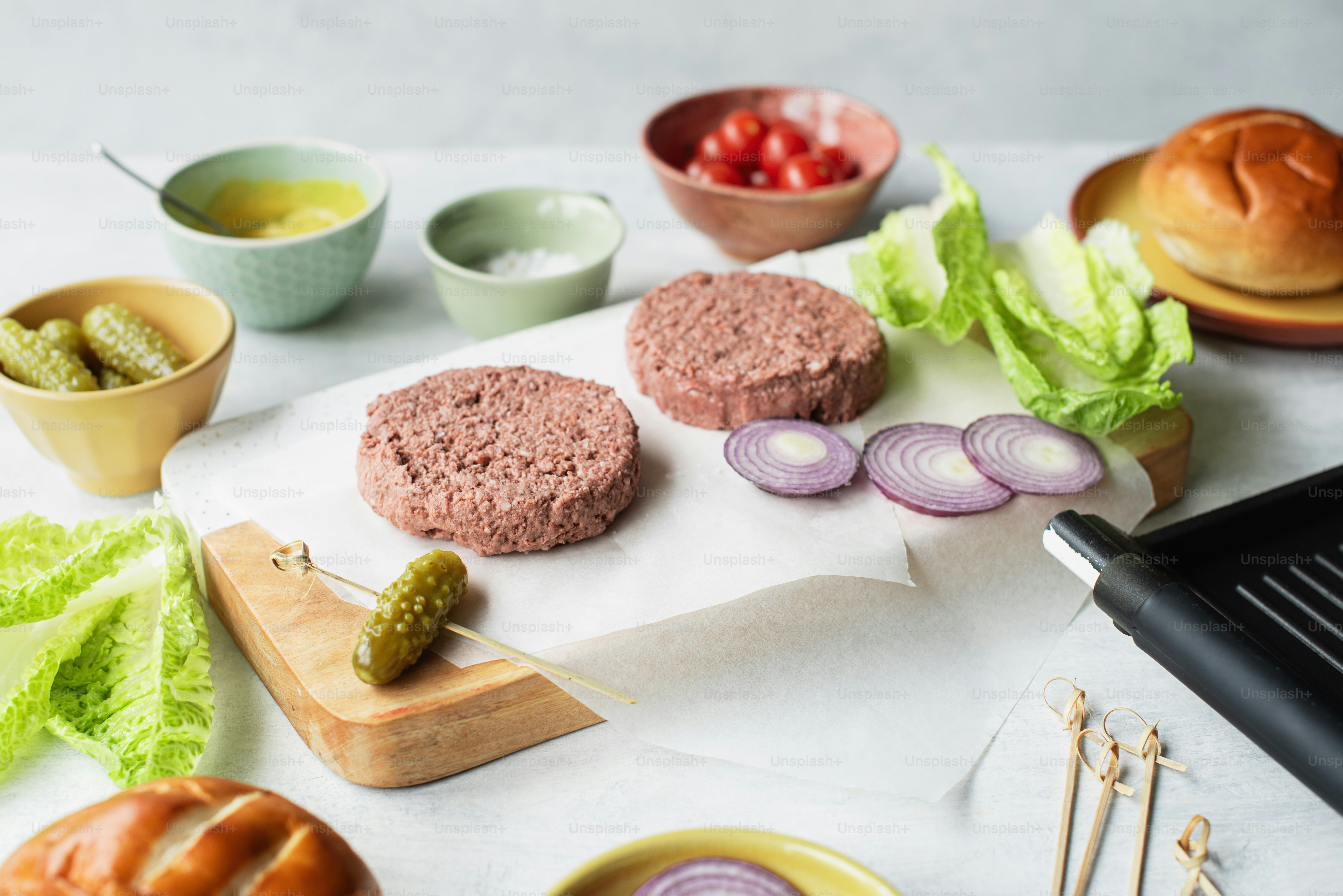 A table topped with hamburgers and other foods photo – Health Image on ...