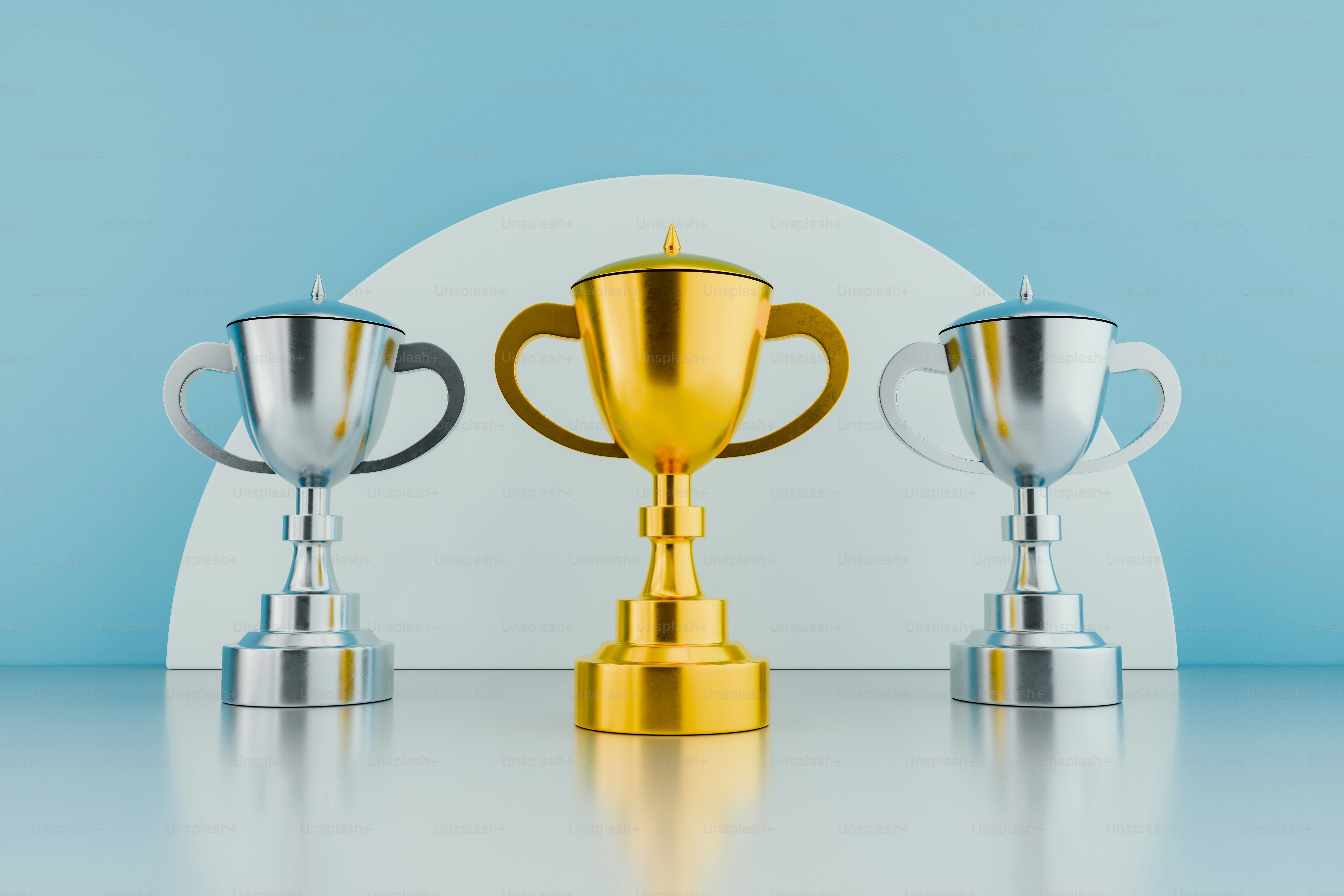 Three silver and gold trophies on a table photo – Gold cup Image on ...