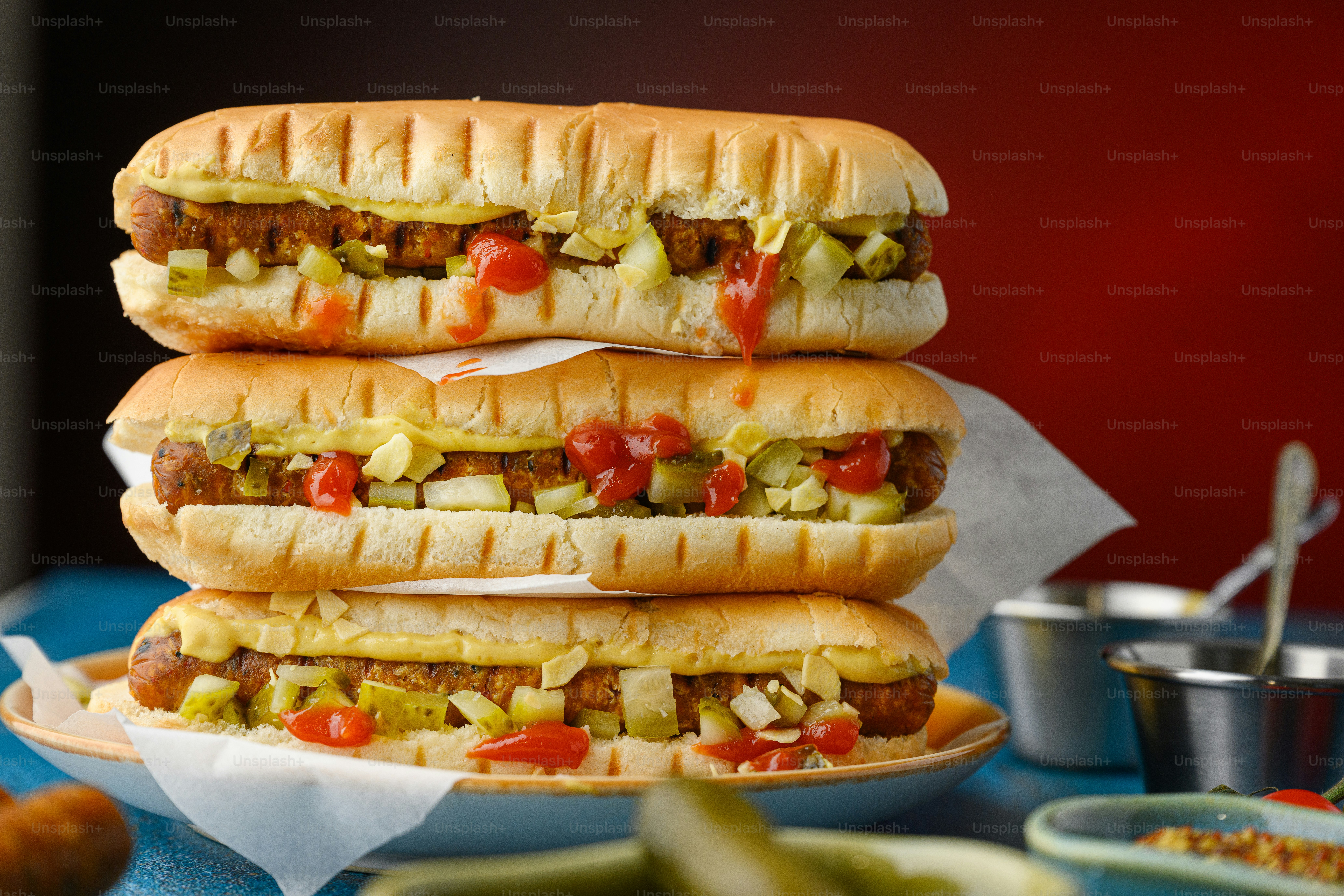 A stack of three hot dogs sitting on top of a table photo – Health ...