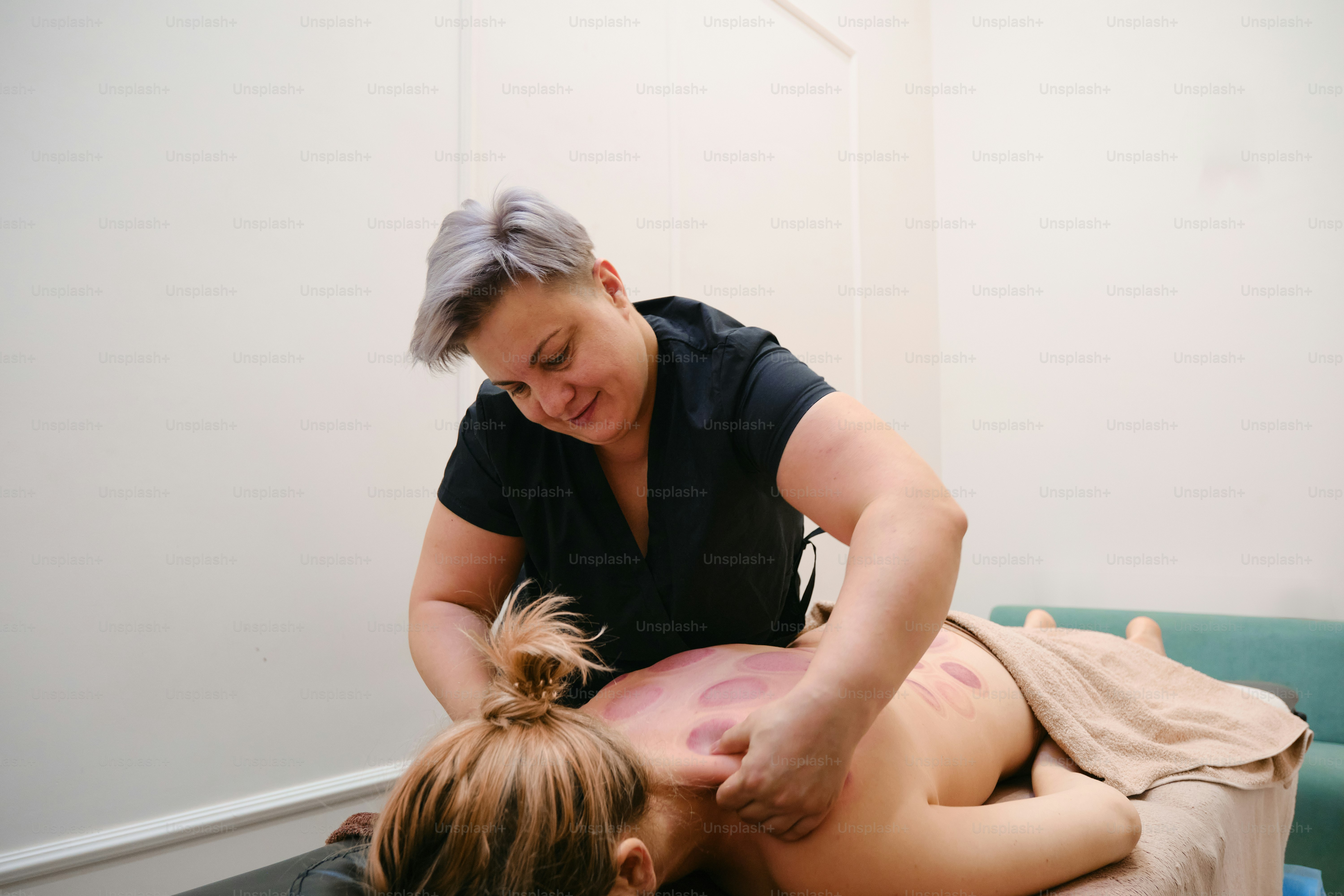 A woman getting a back massage from another woman photo – Therapist ...