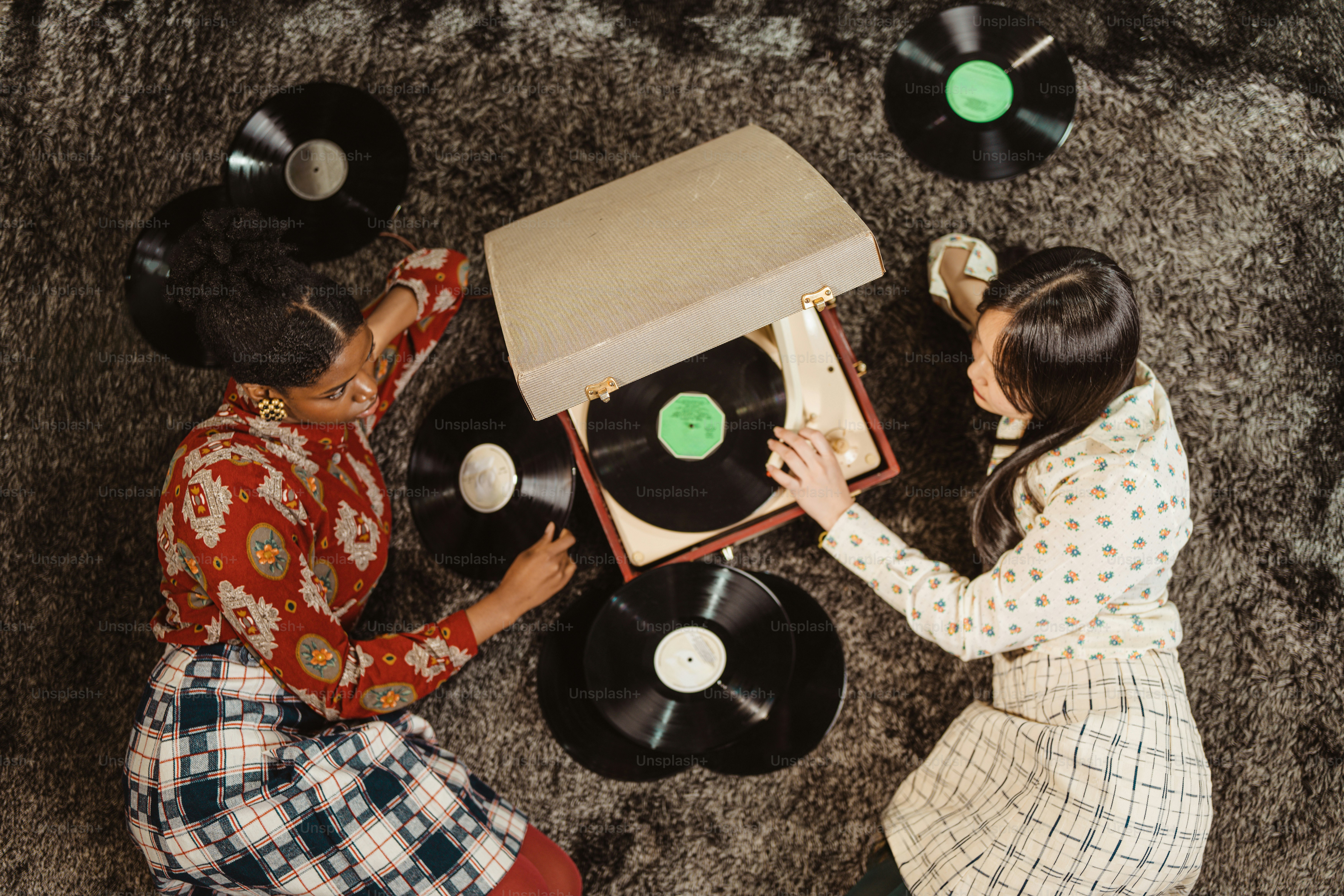 Two women sitting on the floor playing with a record player photo ...