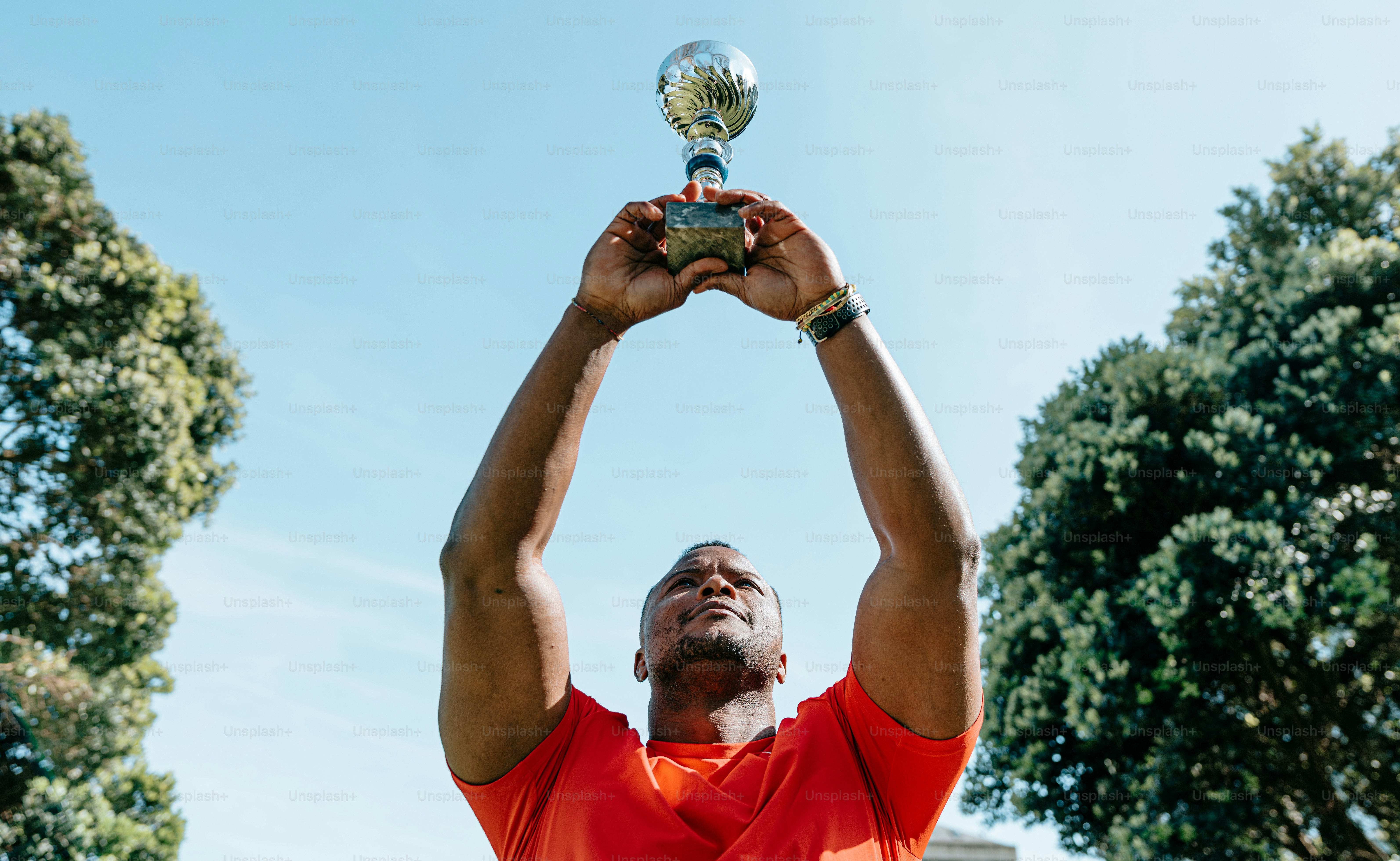 A man holding up a trophy in the air photo – Win Image on Unsplash