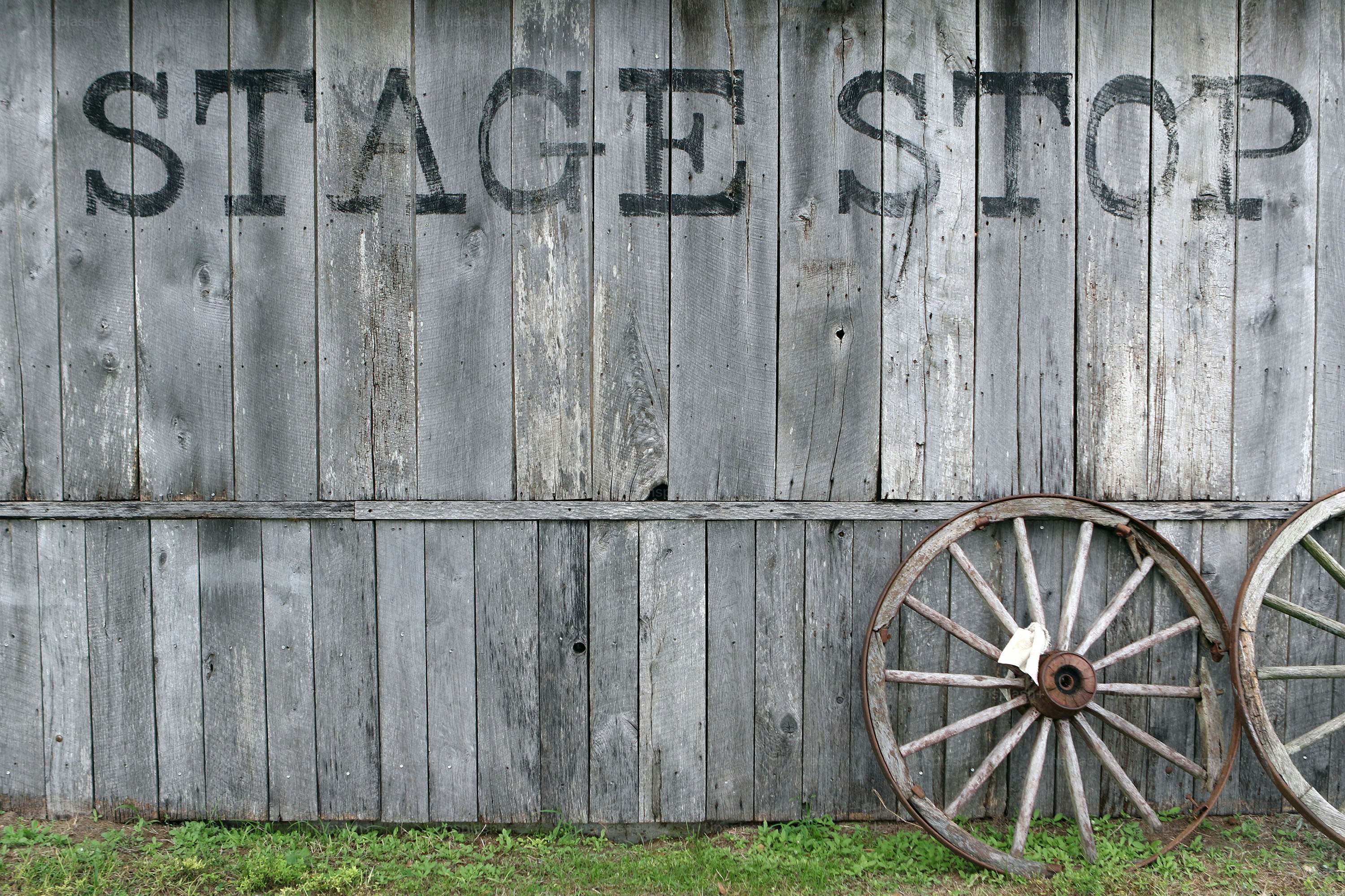 스테이지 스톱(stage stop)이라는 표지판이 있는 나무 벽 사진 – Unsplash의 서쪽의 이미지