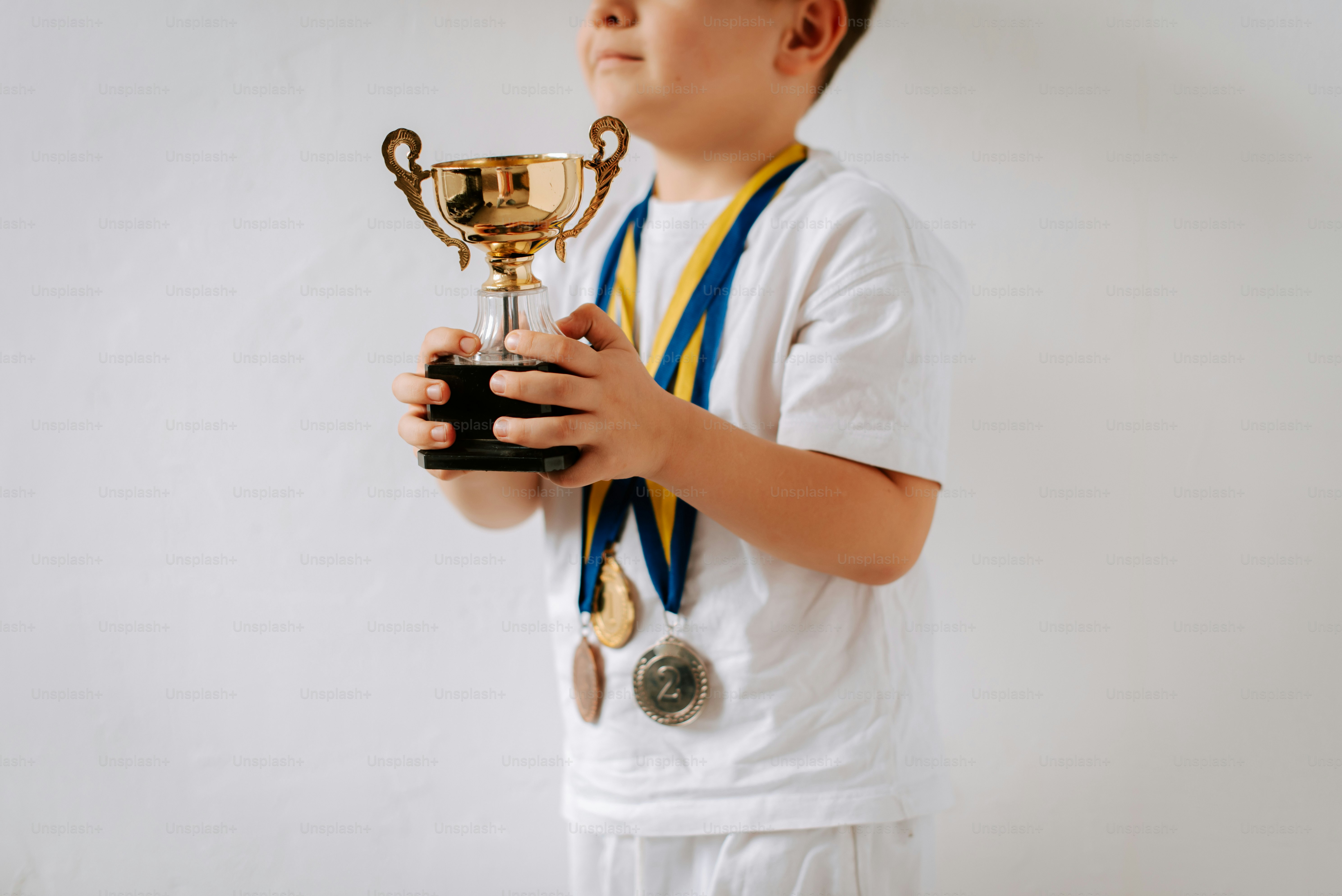 A young boy holding a trophy in his hands photo – Success Image on Unsplash