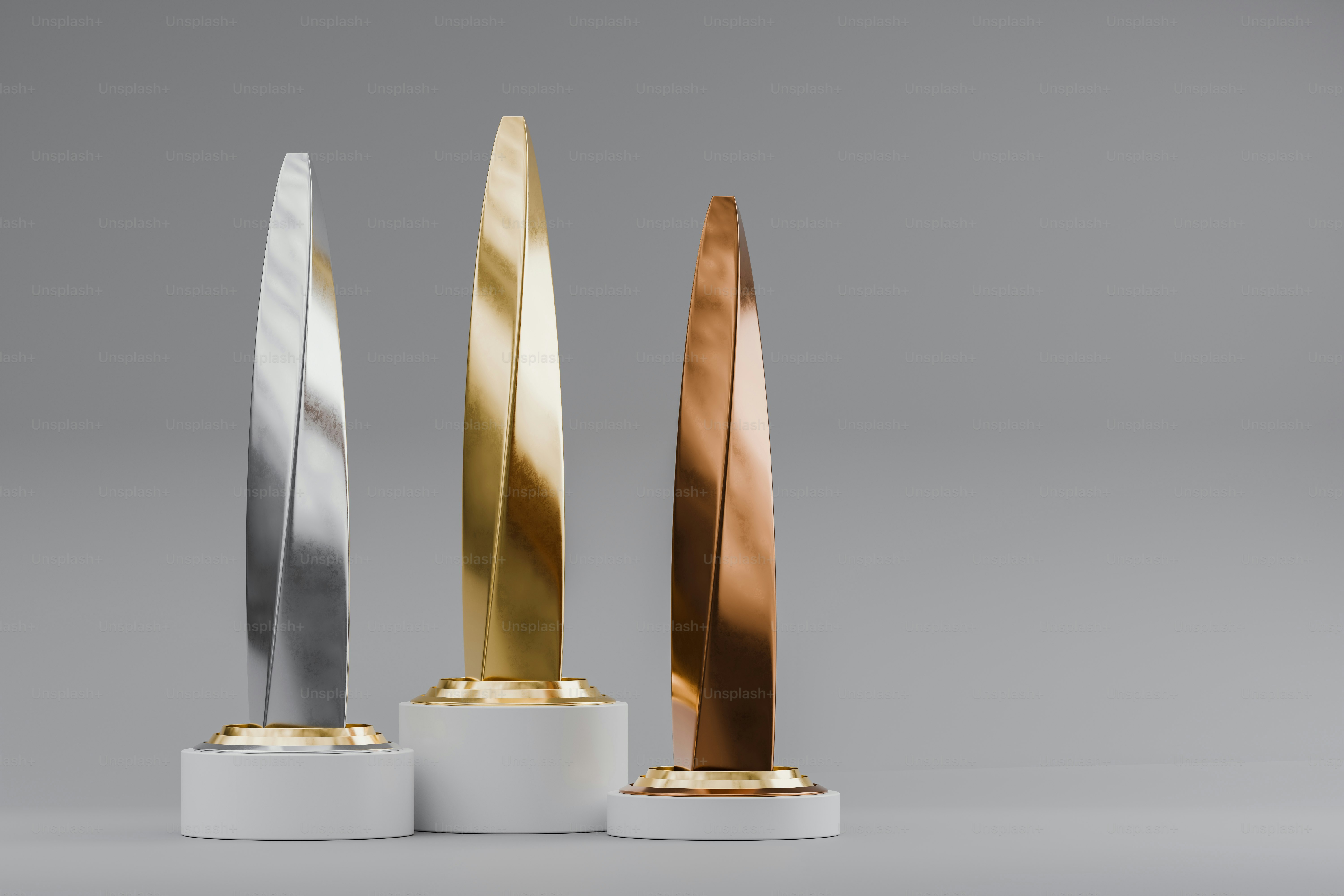 A group of three trophies sitting on top of a white pedestal photo ...