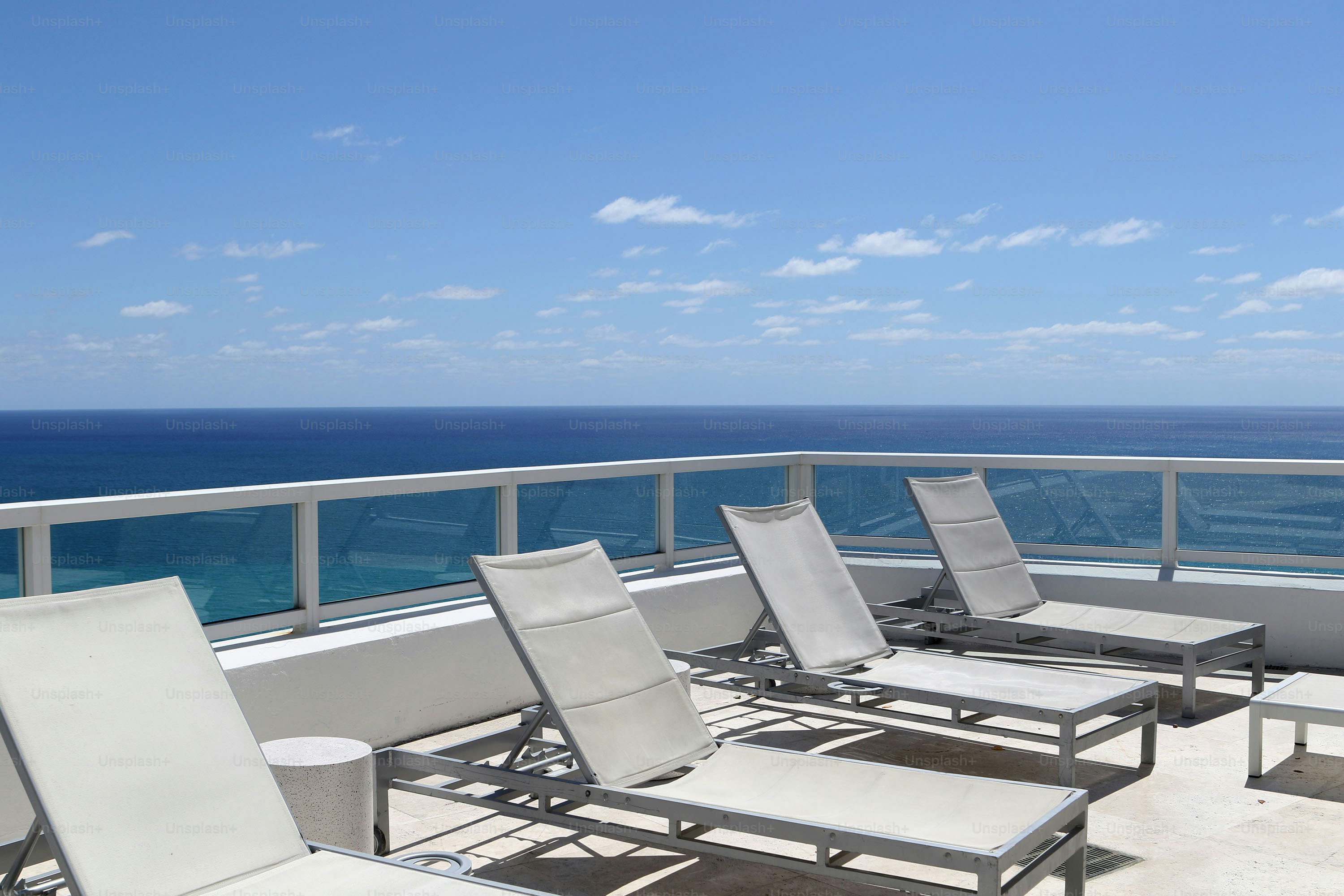 A row of lounge chairs sitting on top of a balcony photo – Furniture ...