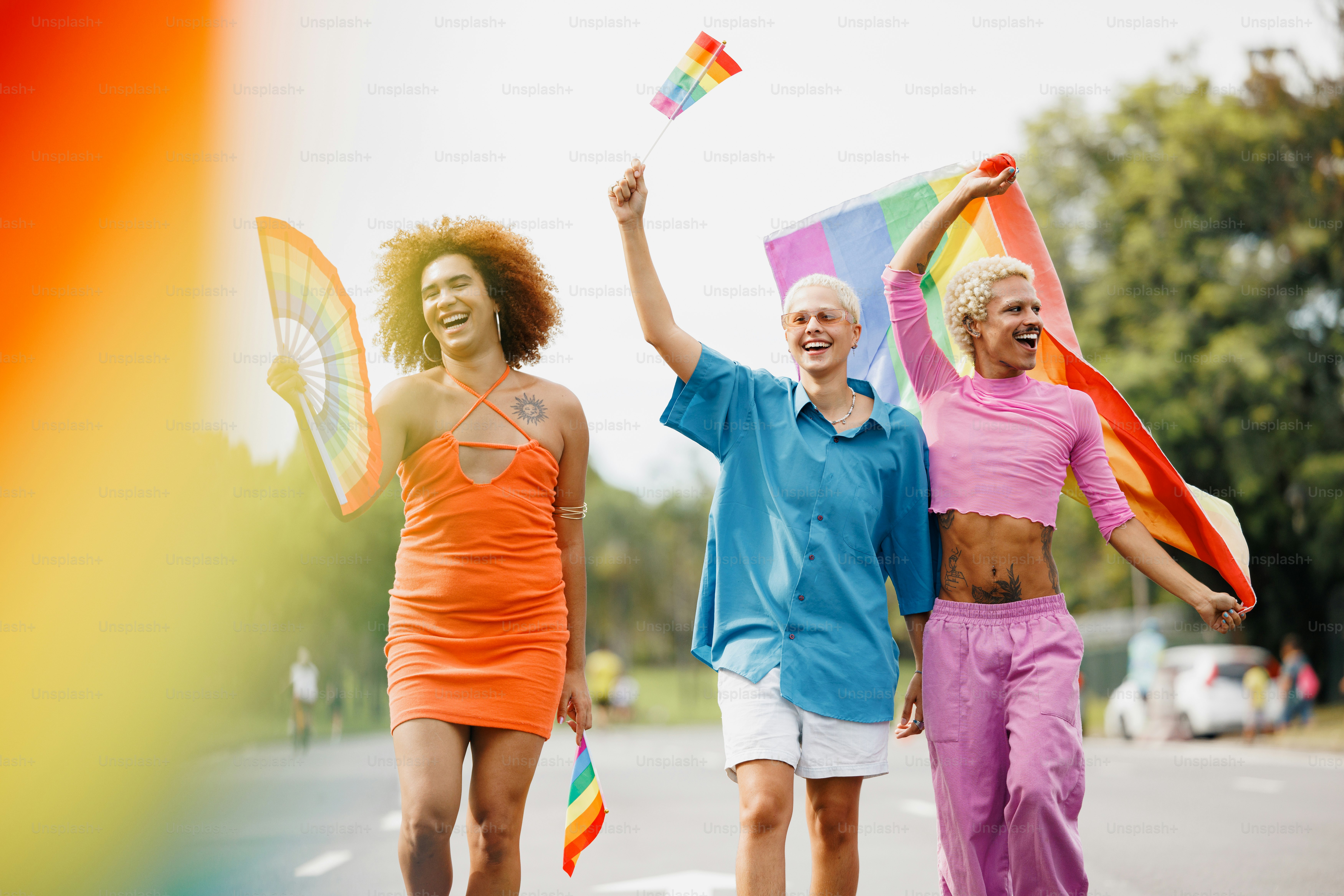 A group of people walking down a street holding kites photo – Pride ...