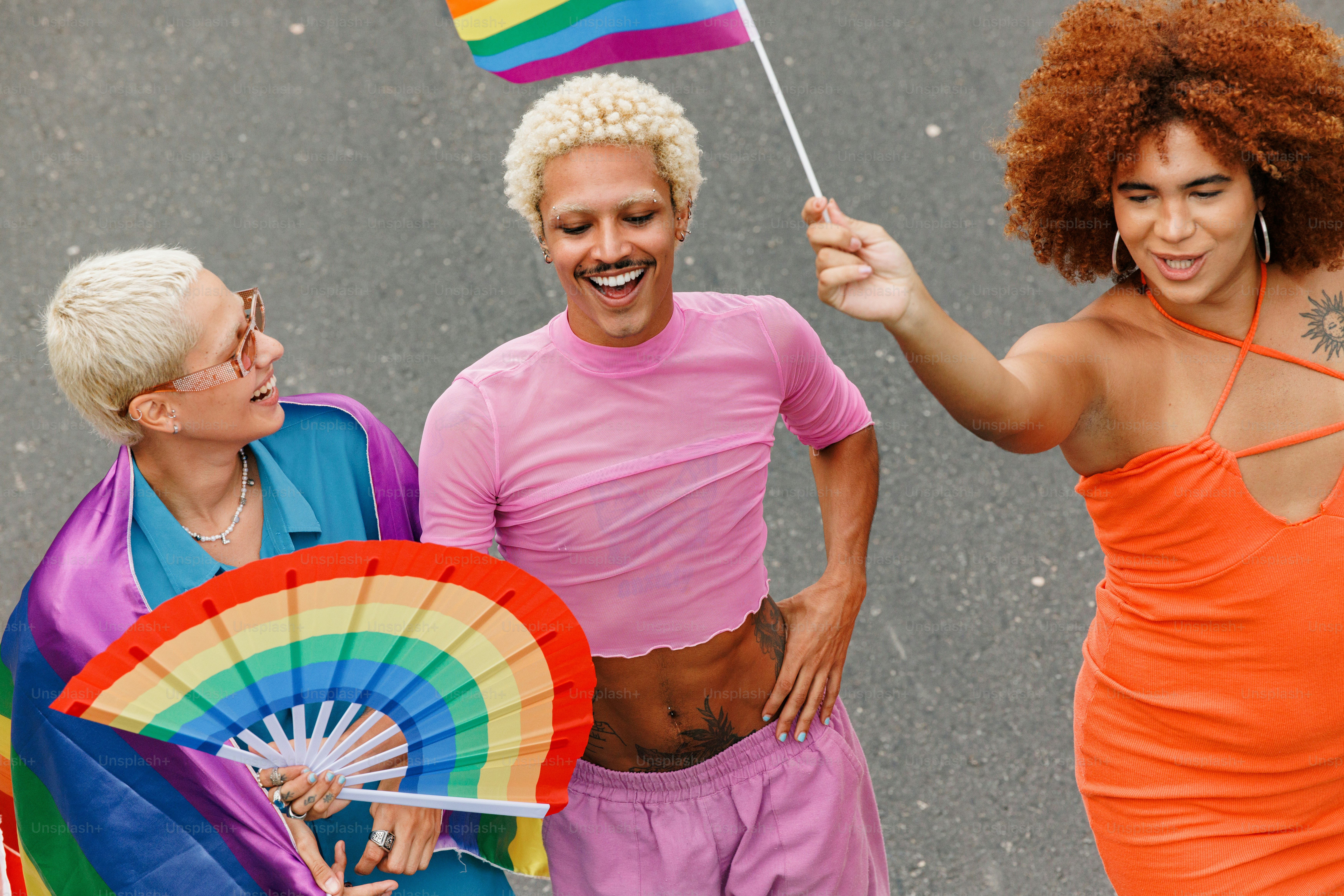 A group of people walking down a street holding a rainbow flag photo ...