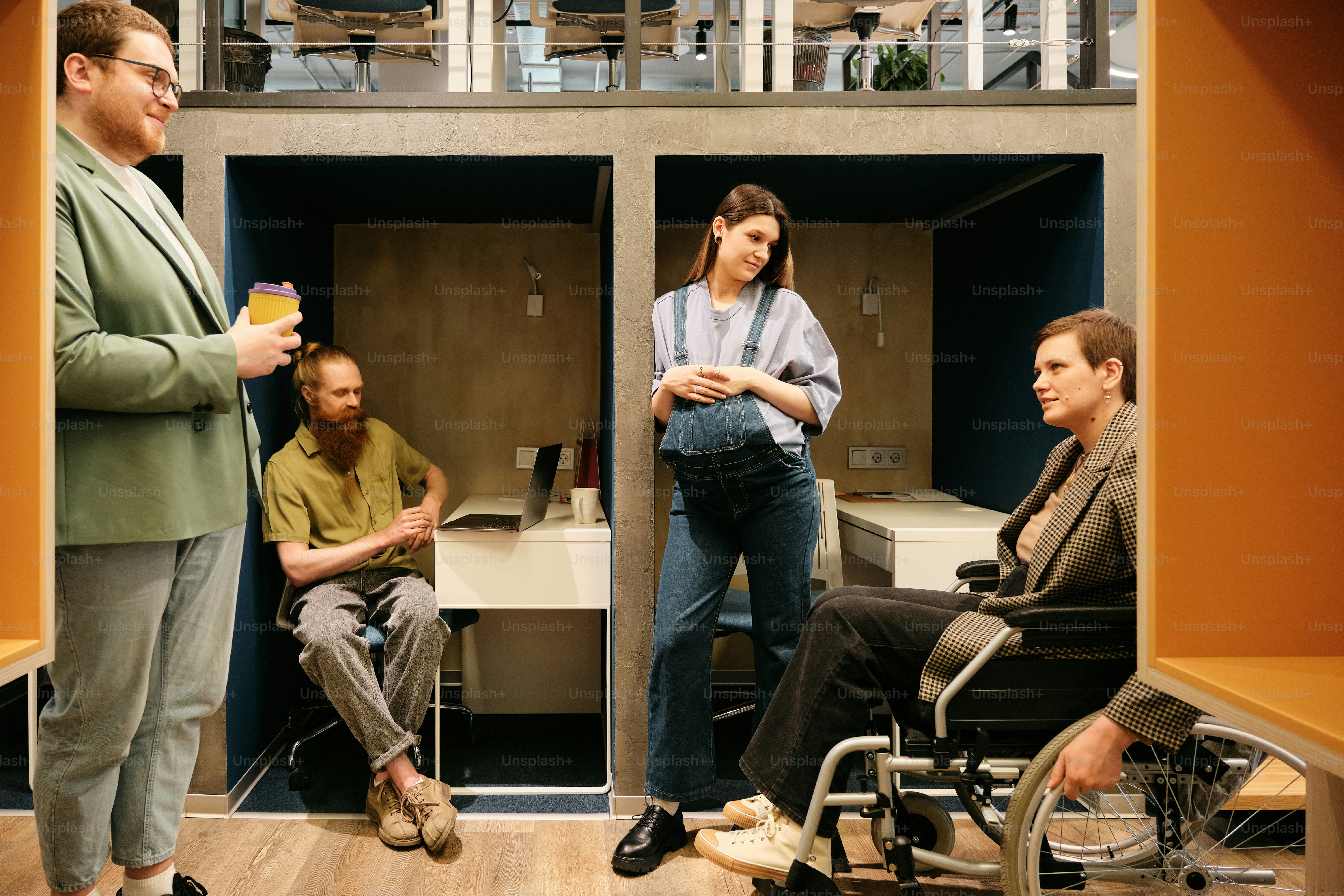 A group of people standing and sitting around a room photo – Office ...