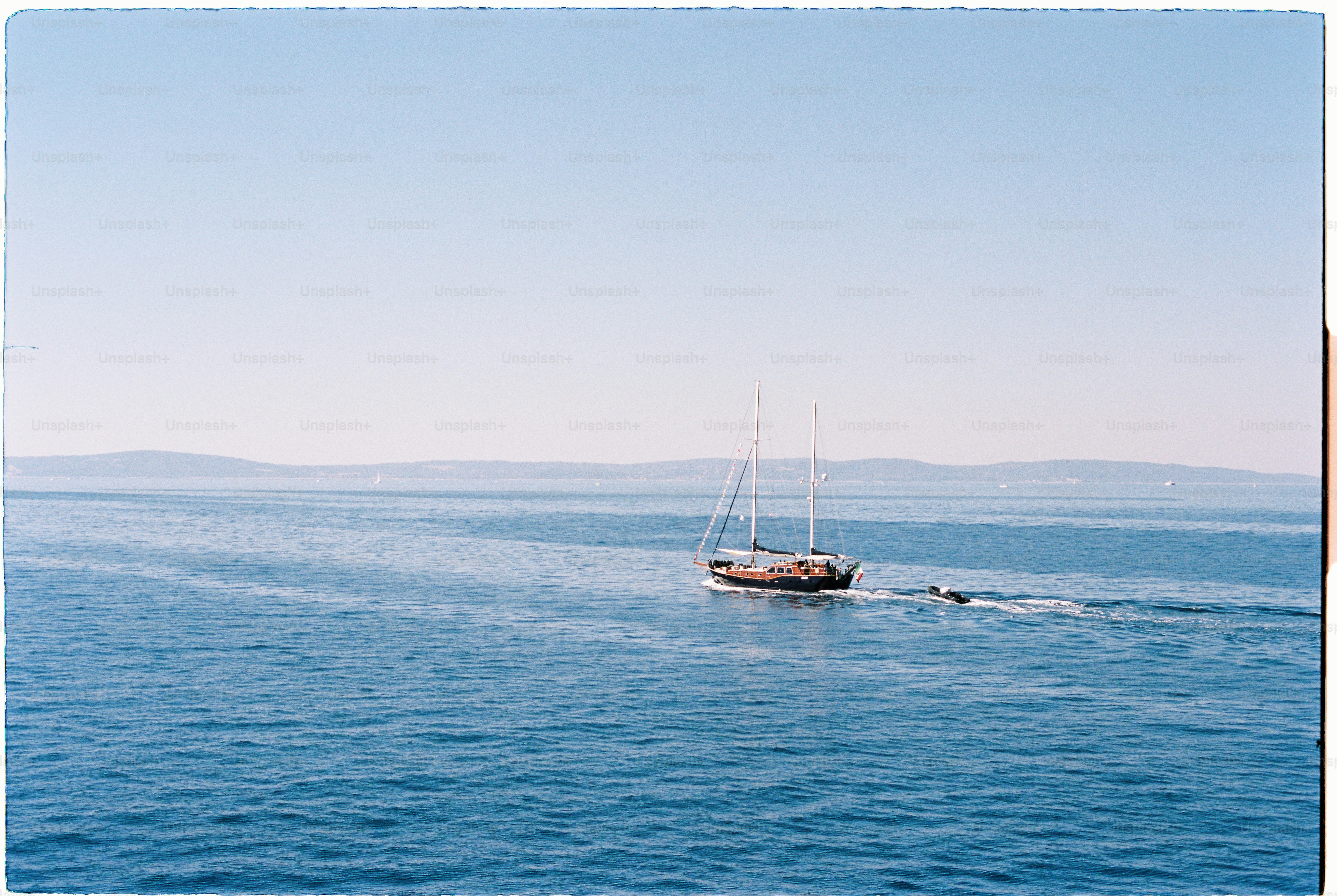 A sailboat sailing across a large body of water photo – Ocean Image on ...