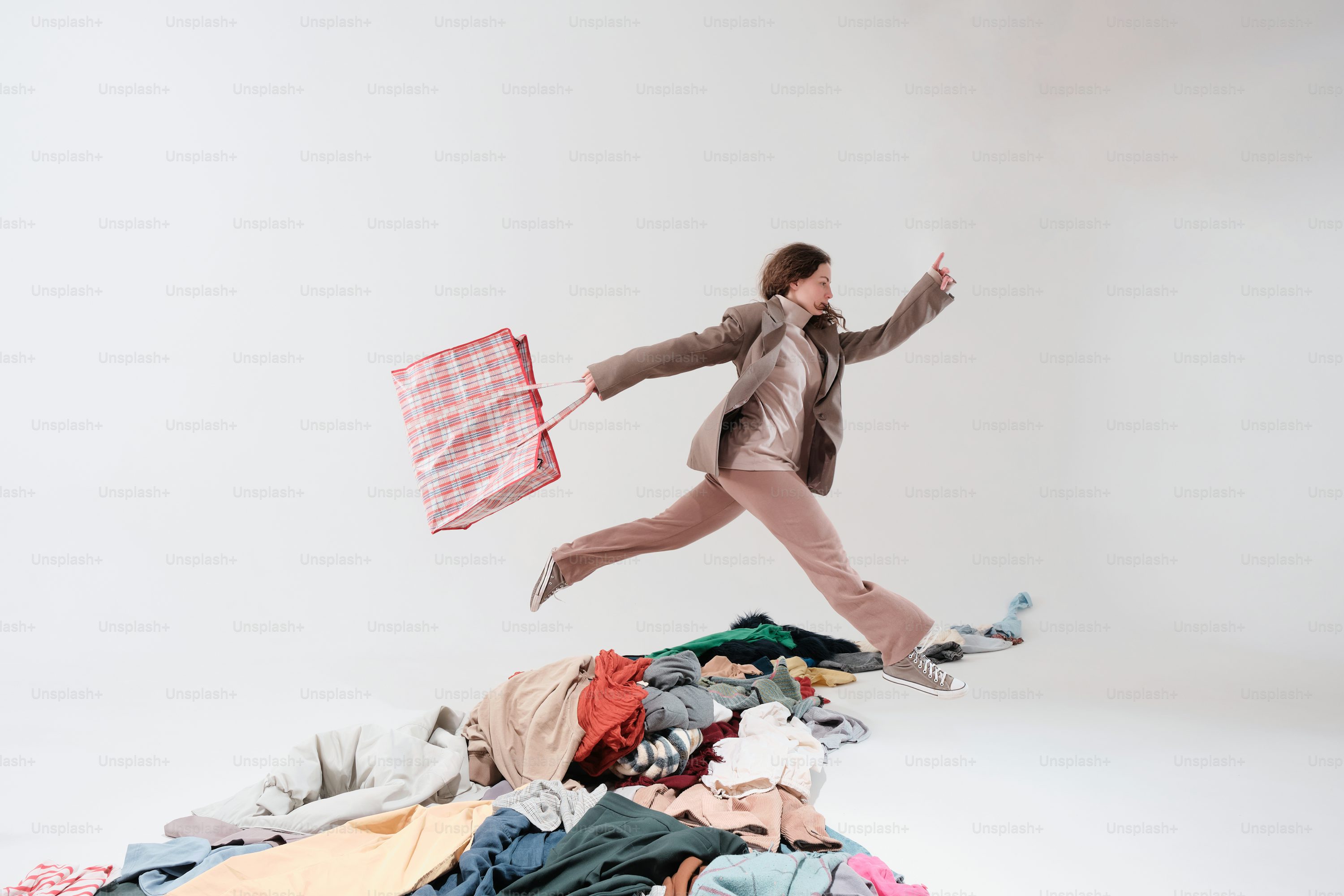 Eine Frau, die über einen Haufen Kleidung in die Luft springt Foto ... Eine Frau, die über einen Haufen Kleidung in die Luft springt Foto ...