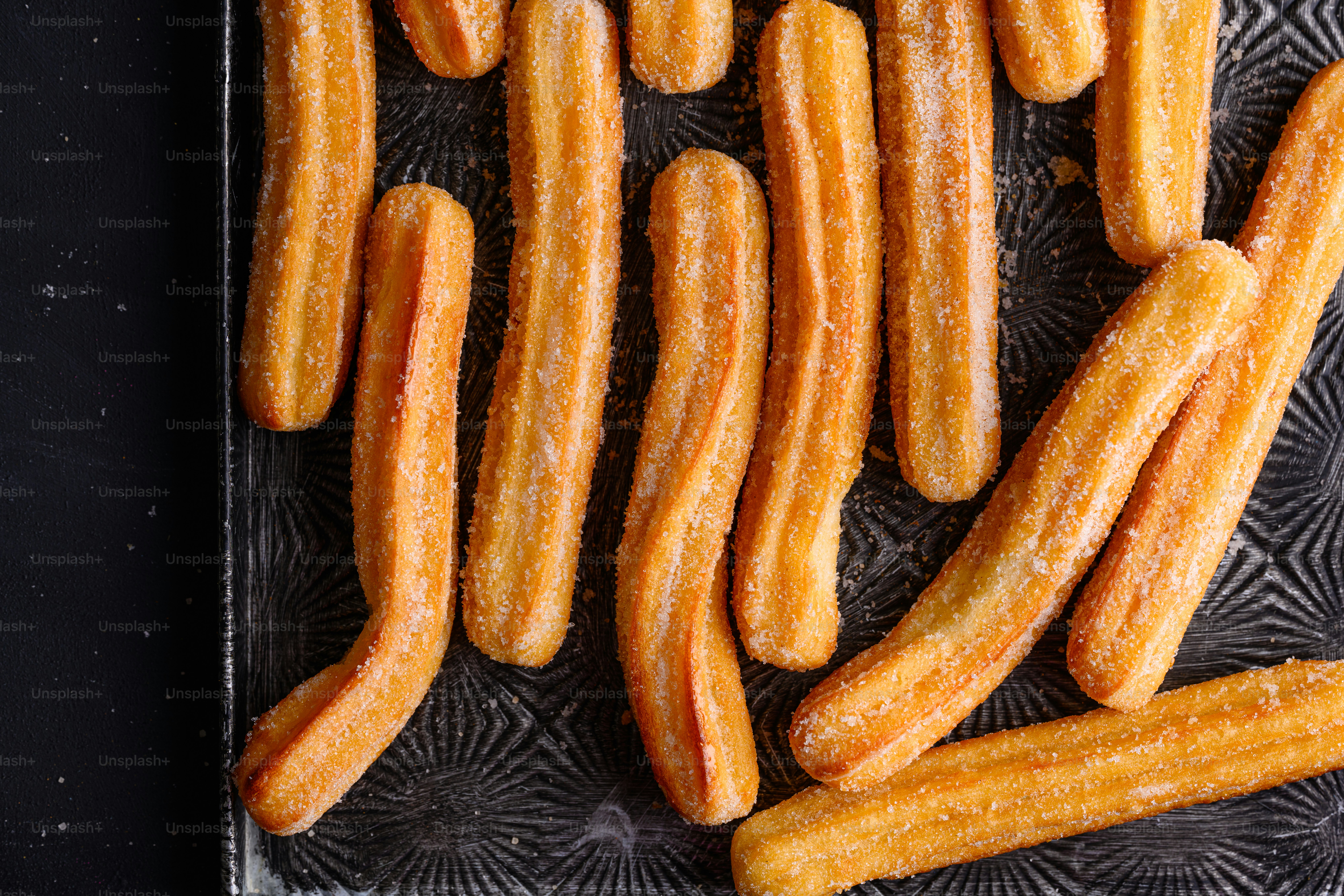 A bunch of churros sitting on top of a black tray photo – Food styling ...