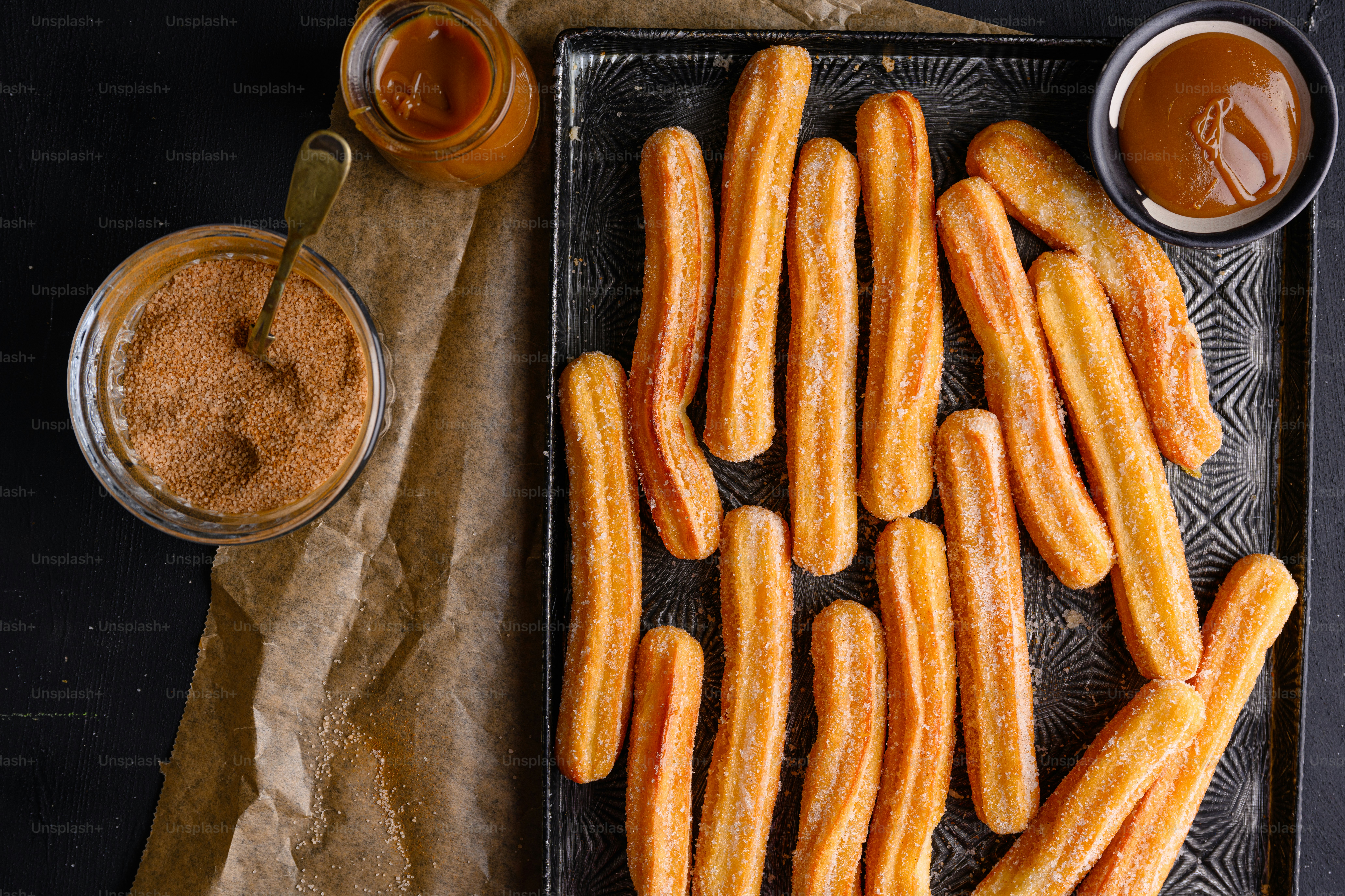 A tray of churros next to a cup of sauce photo – Culinary Image on Unsplash