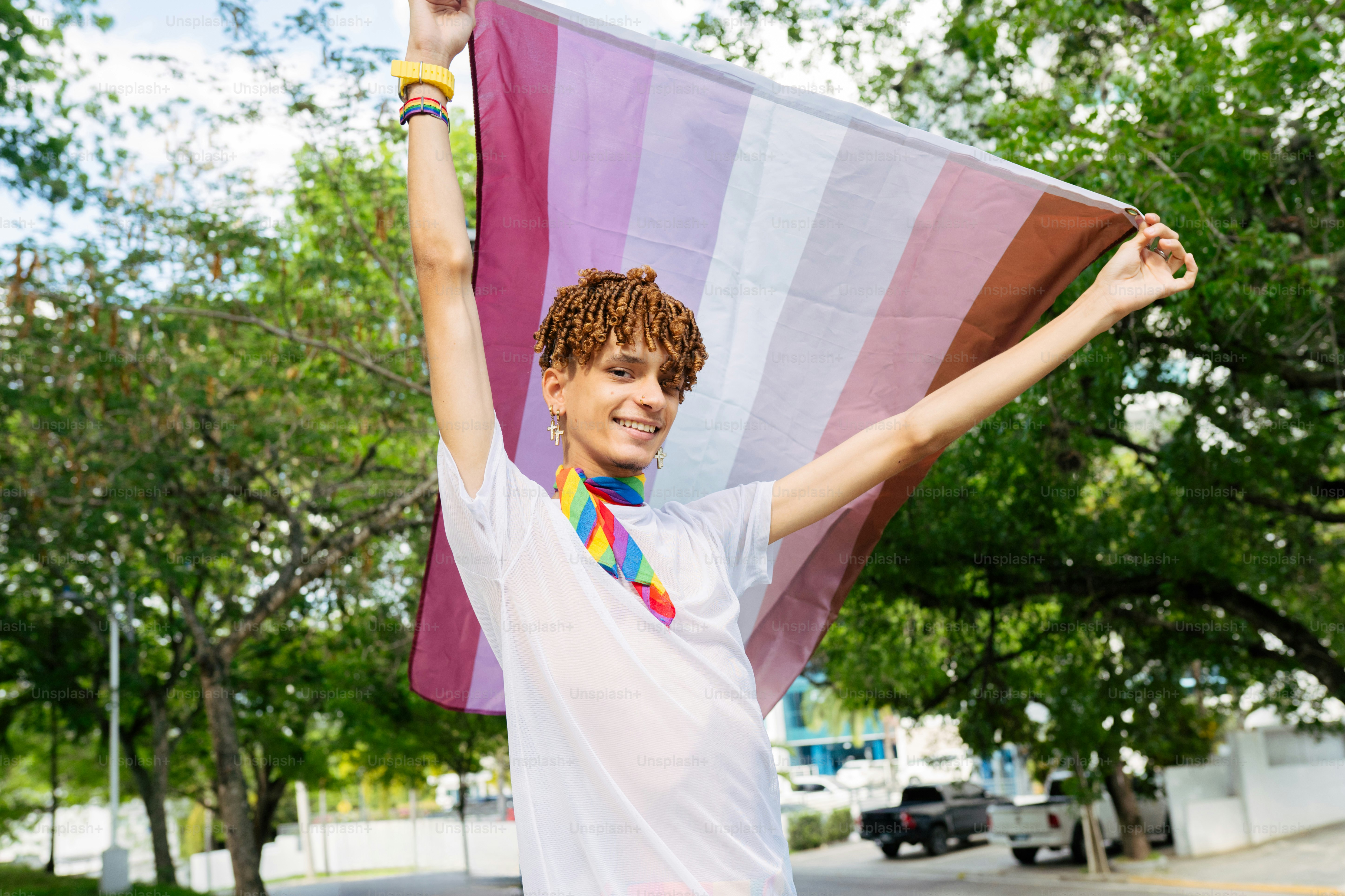 A young man holding a rainbow colored flag photo – Pride parade Image ...