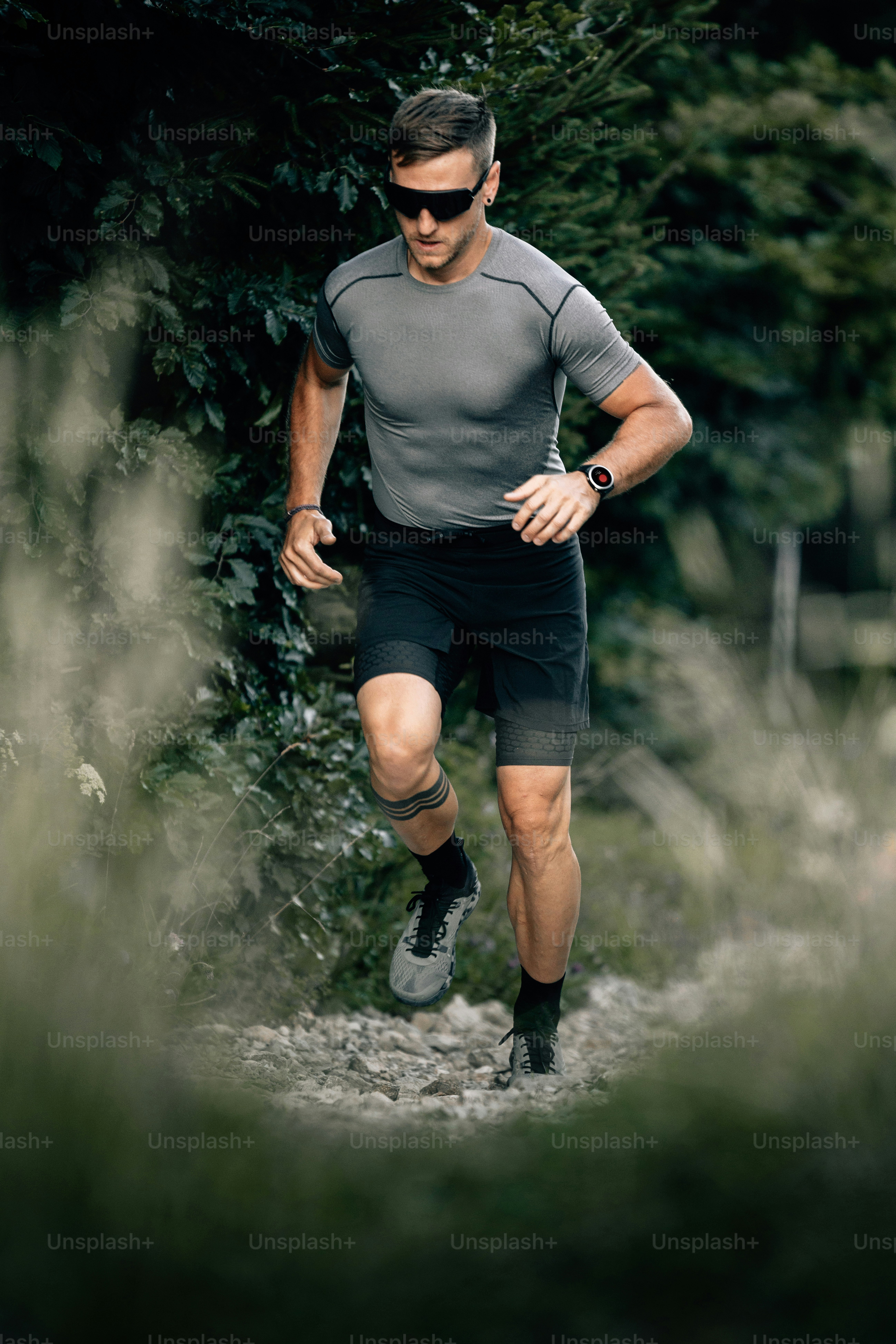 A man in a gray shirt and black shorts running photo – Runner Image on ...