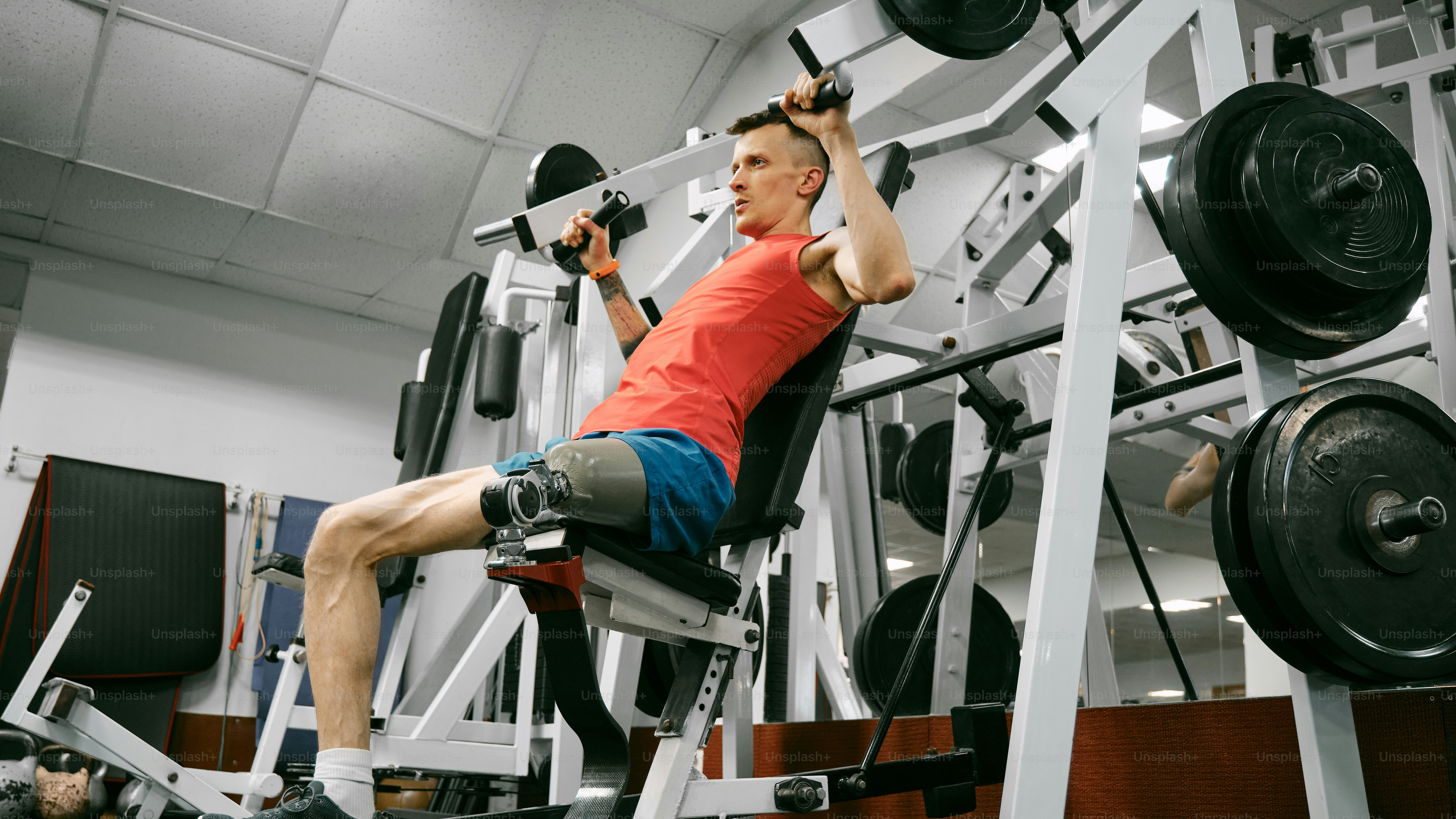 A man doing a bench press in a gym photo – Amputee athlete Image on ...