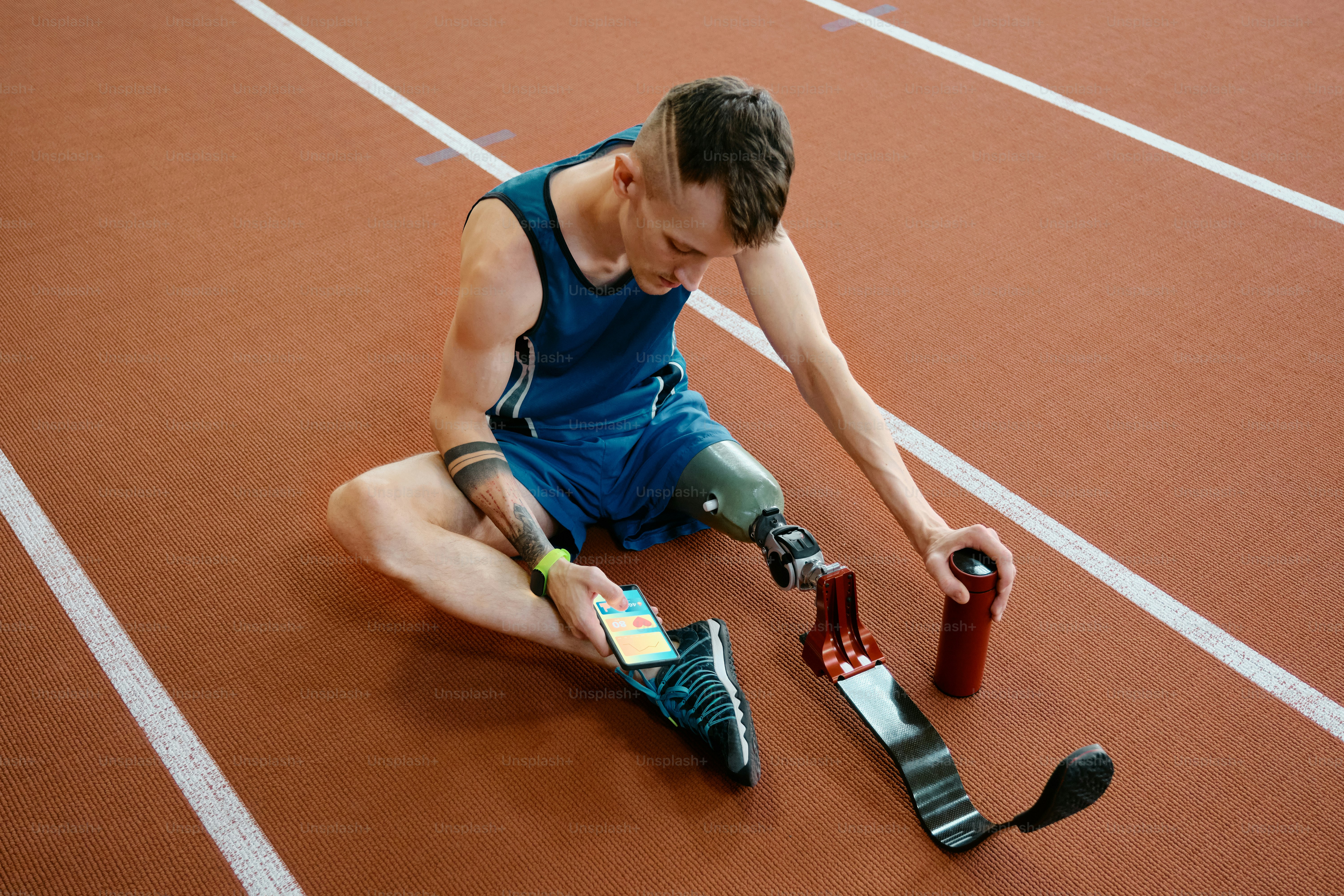 A man sitting on a track tying his shoes photo – Amputee athlete Image ...
