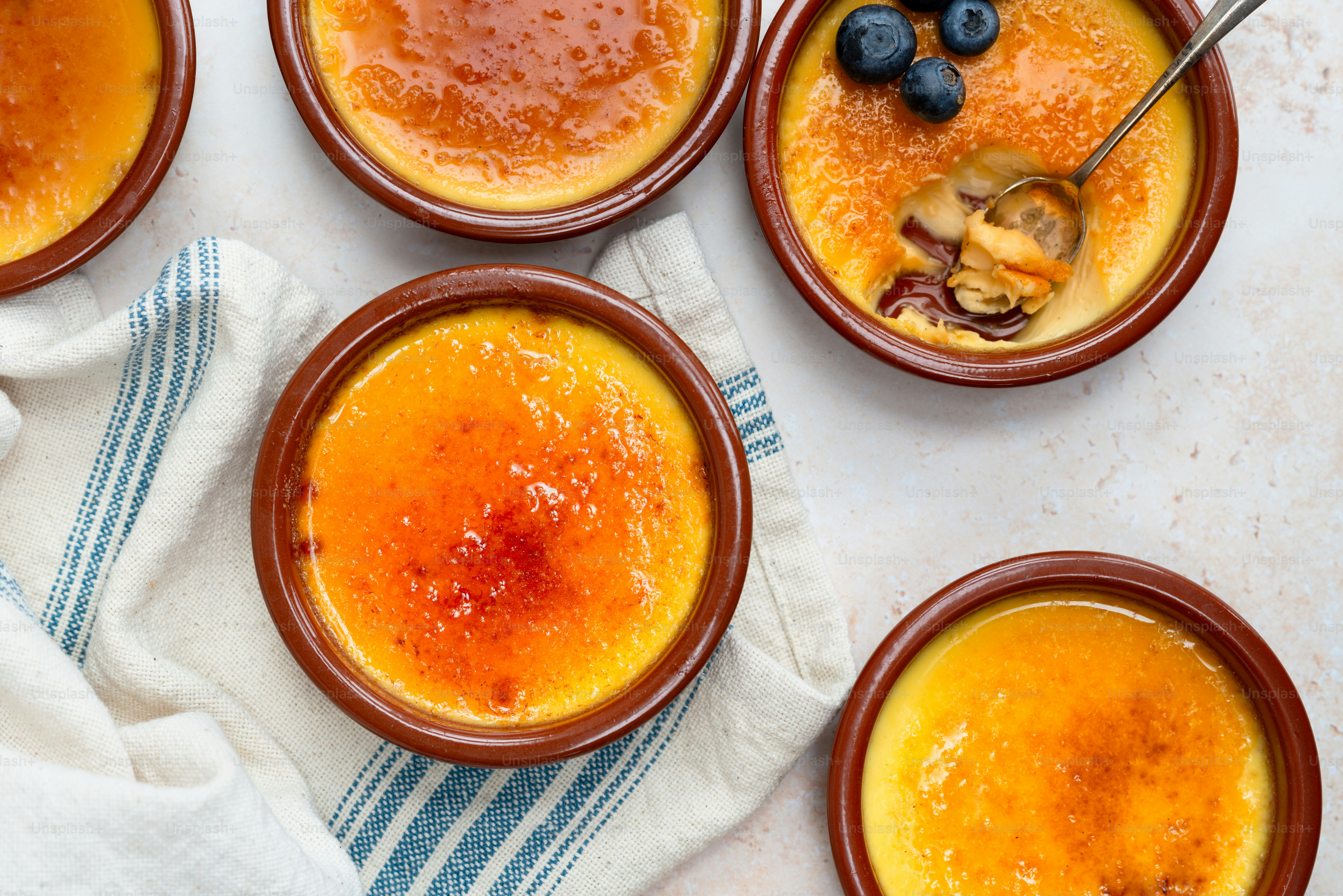 A table topped with four bowls of food photo – Creme brule Image on ...