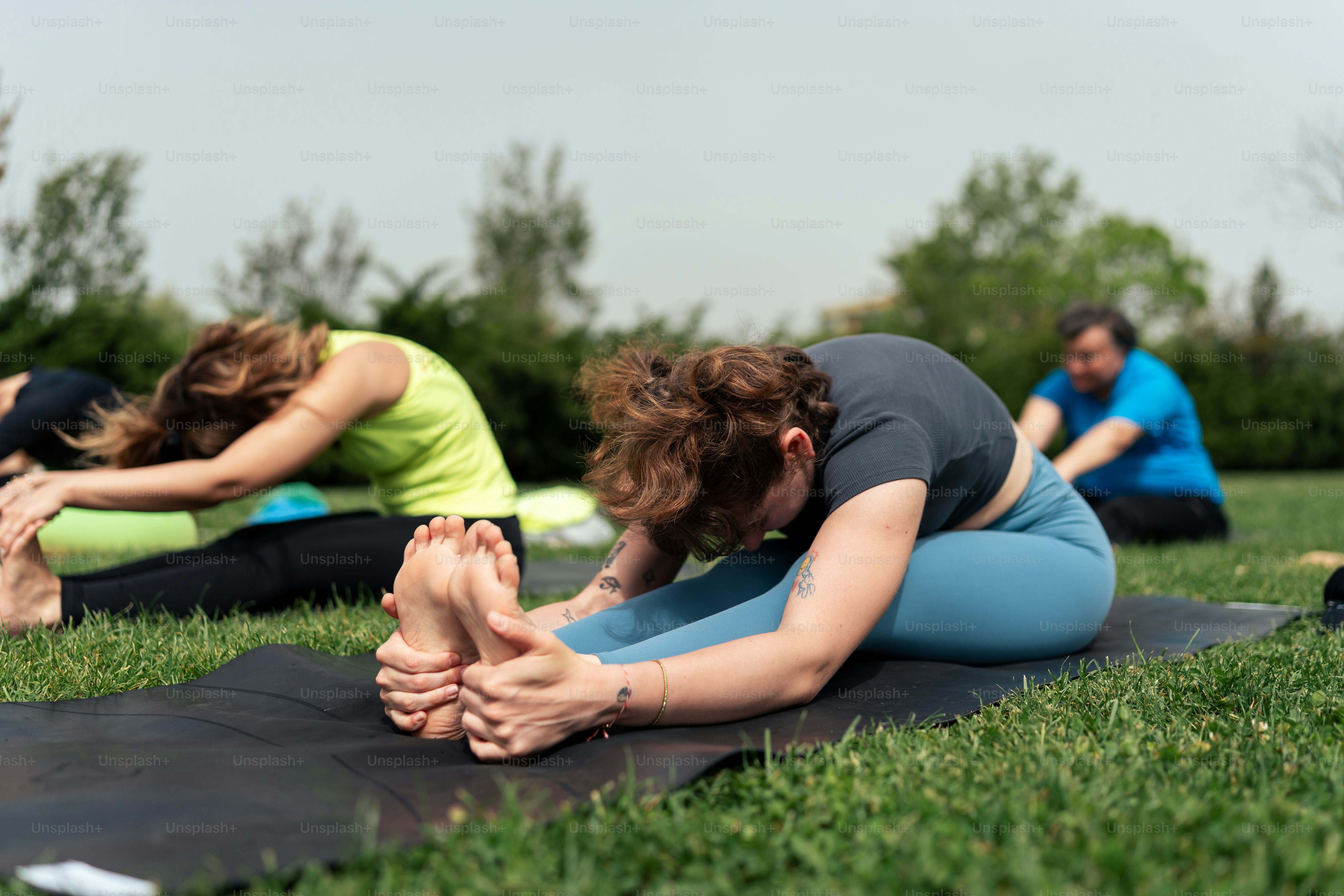 A group of people doing yoga in a park photo – Yoga retreat Image on ...