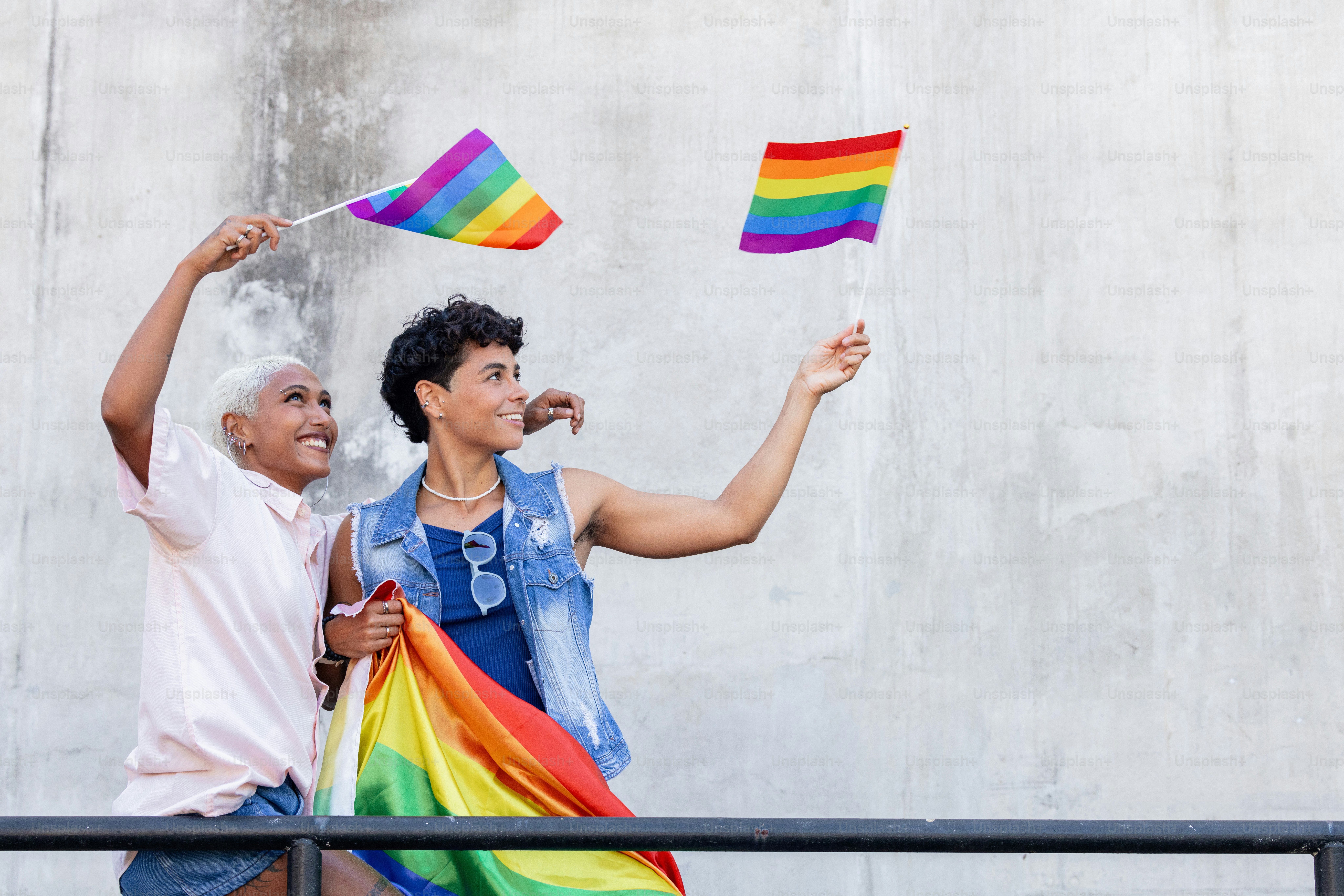 A couple of people that are holding flags photo – Rainbow flag Image on ...