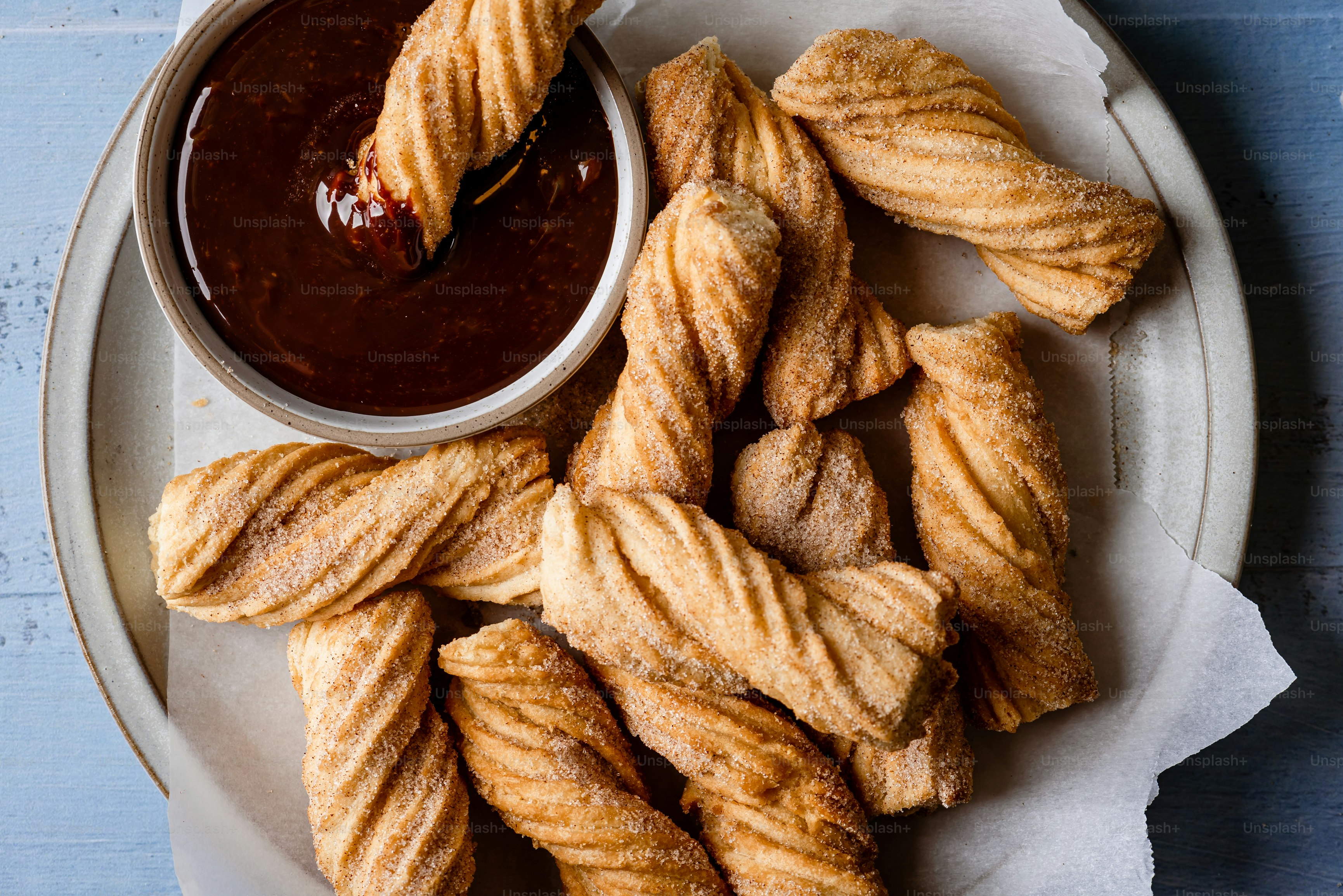 A white plate topped with pastries next to a bowl of dipping sauce ...