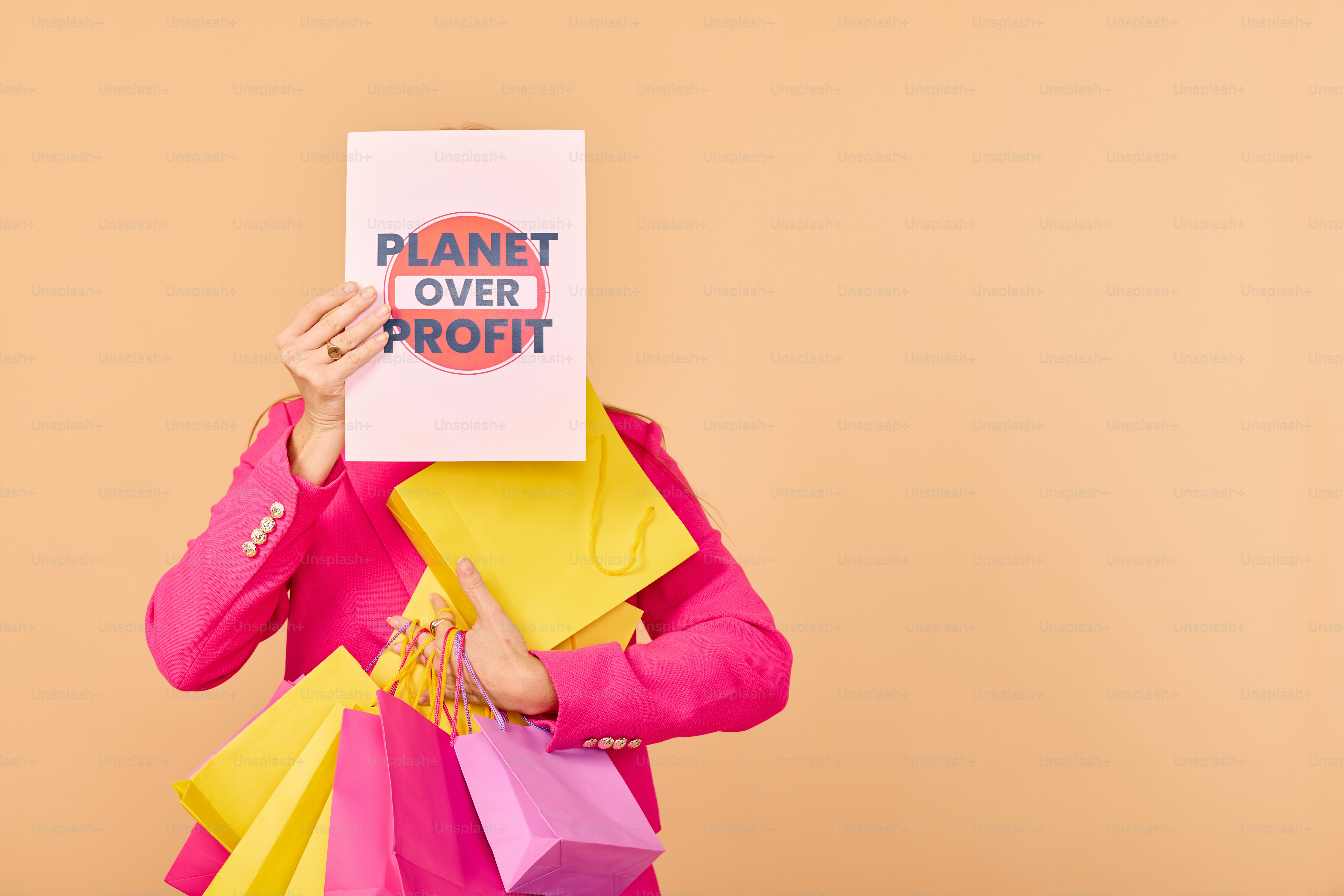 A woman holding a sign that says planet over profits photo – Consumerism Image on Unsplash